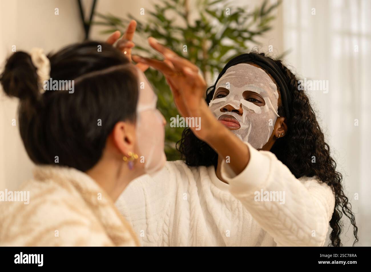 Two friends are enjoying a relaxing home spa day, applying revitalizing ...