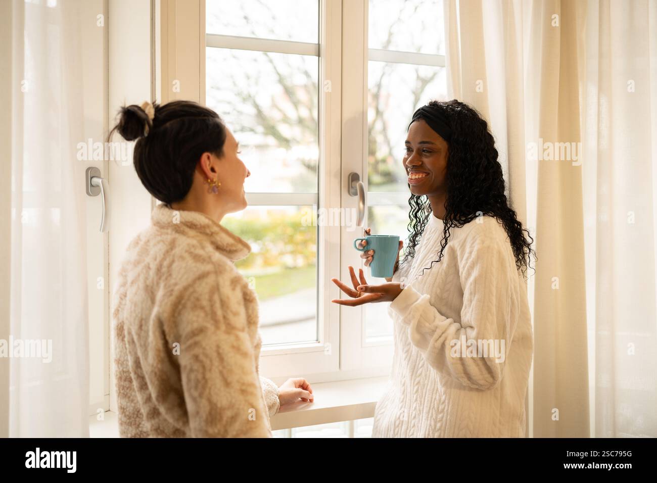 Two cheerful women, possibly roommates or friends, engage in a friendly ...