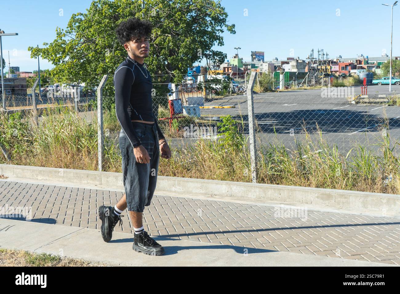 Young Hispanic African man walking seriously on a sidewalk next to an ...