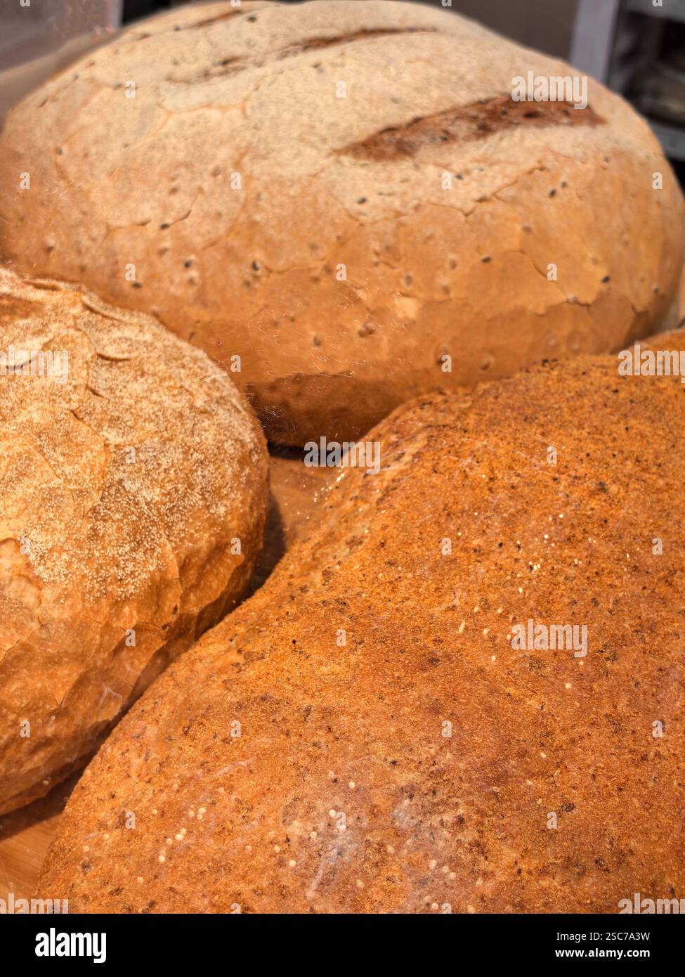 Golden brown loaves of artisanal bread rest on a wooden surface in a ...
