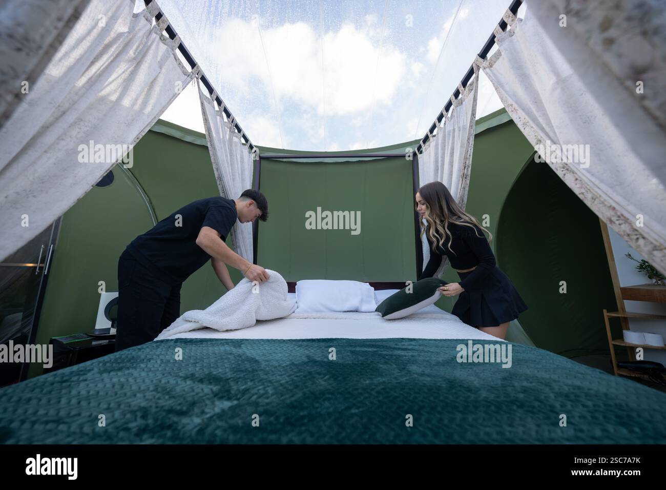 Two young hotel employees working together to make the bed inside a ...