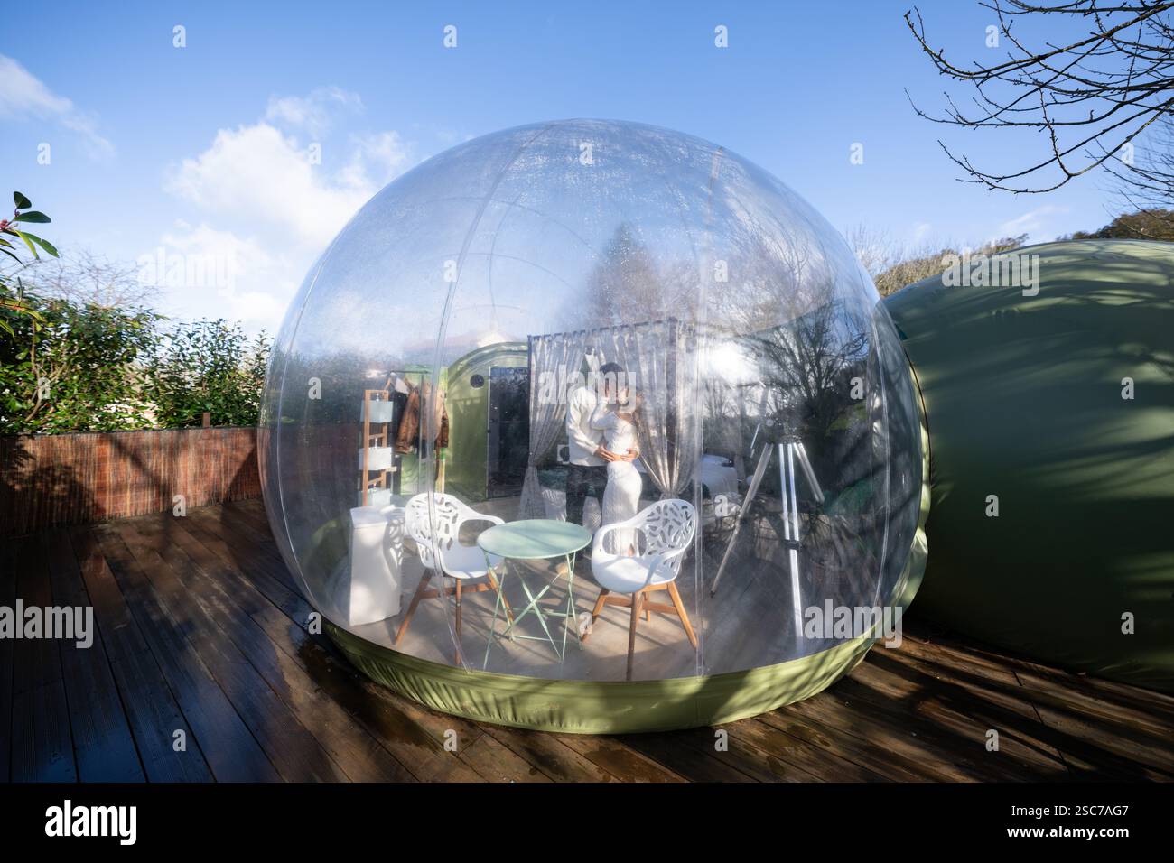 Romantic couple embracing inside a transparent bubble hotel room ...
