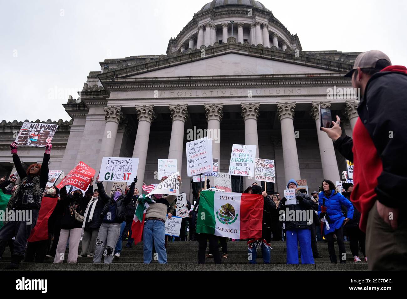 People wave signs as they gather to protest against the Trump ...