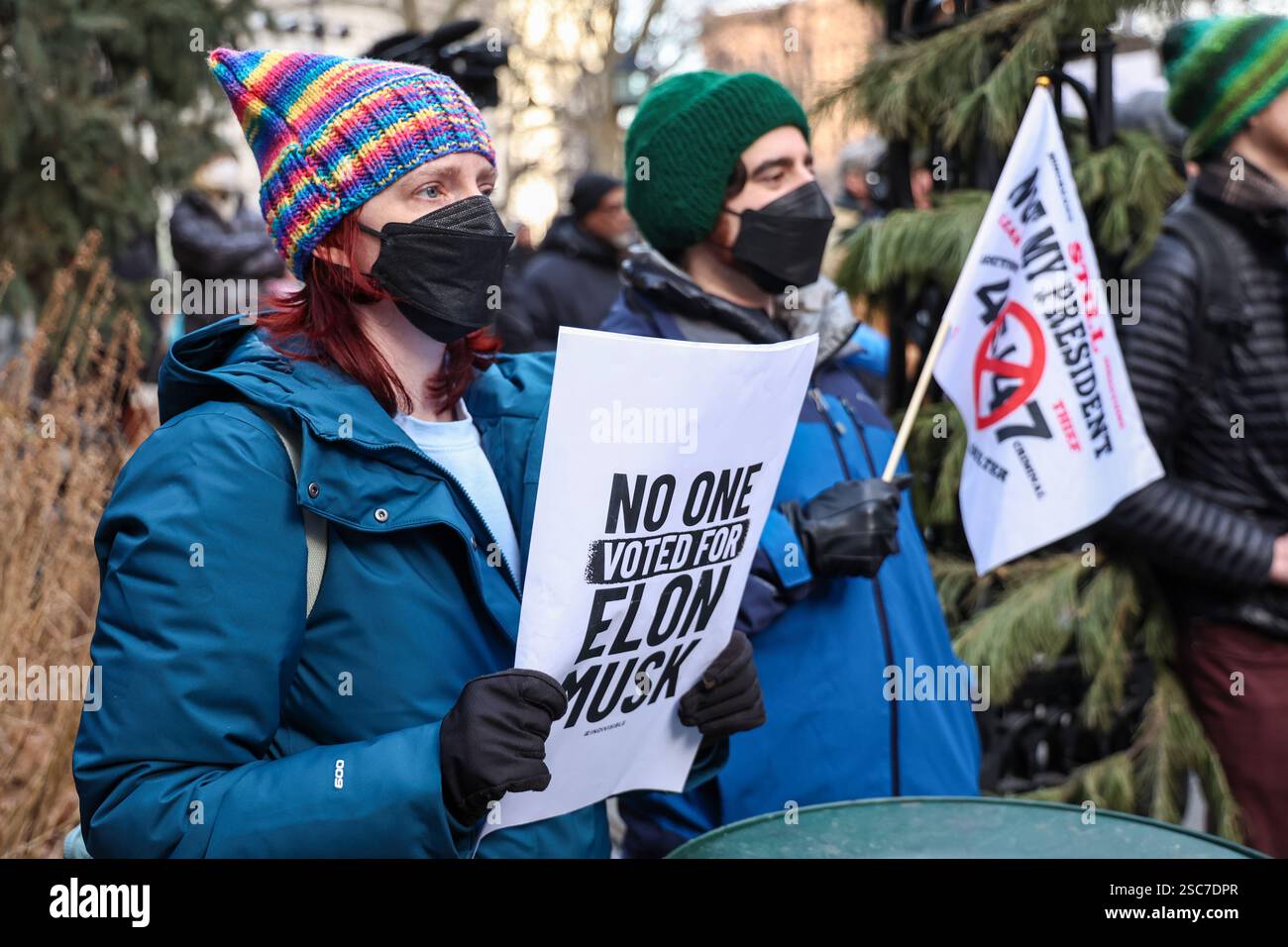 A protester holds up a sign addressing Elon Musk's involvement in ...