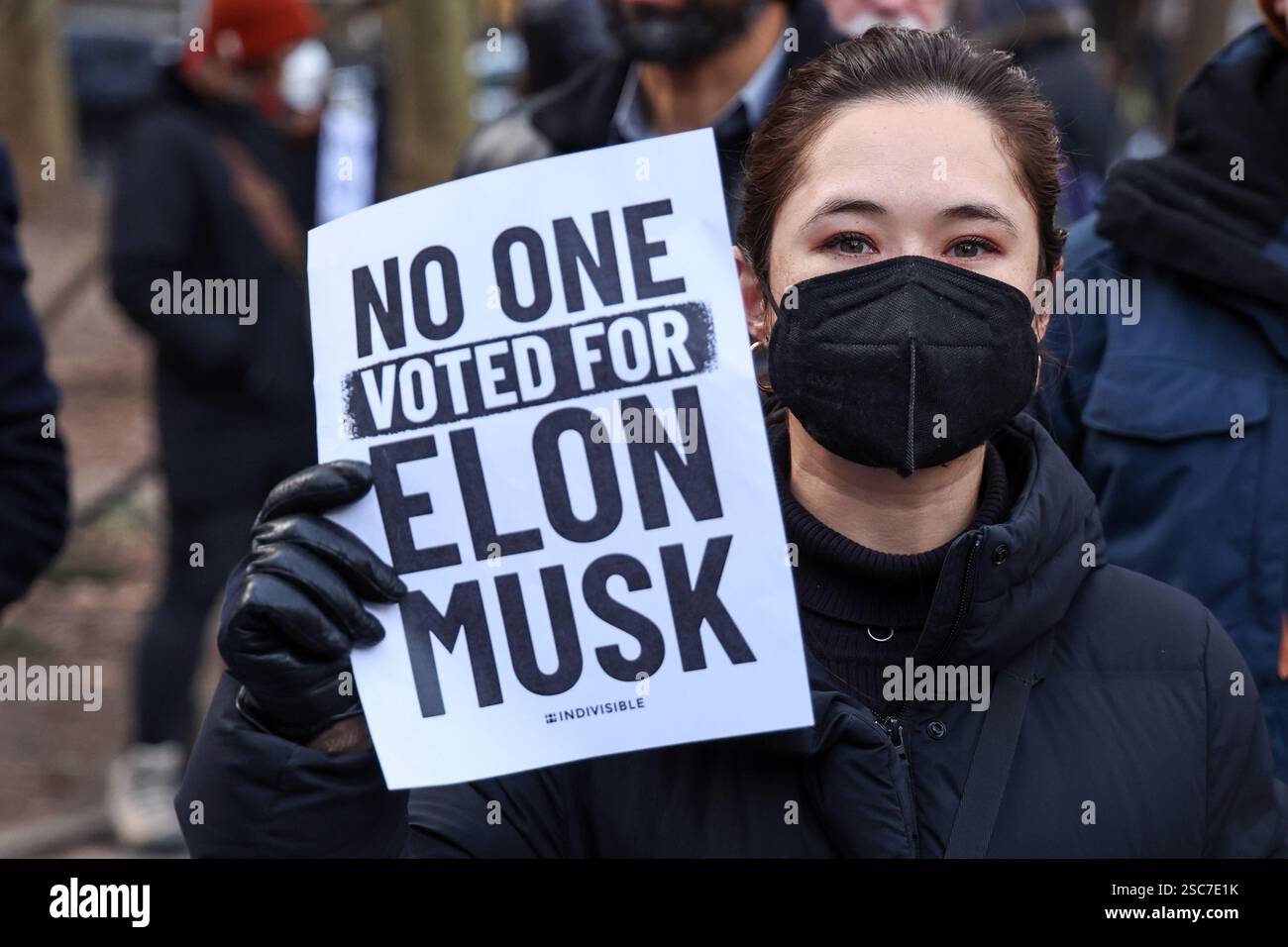A protester holds up a sign addressing Elon Musk's involvement in ...