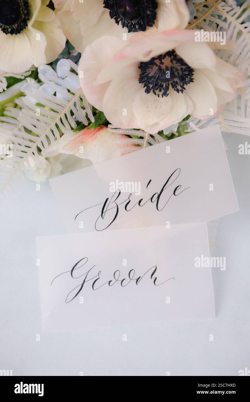 Delicate name cards for bride and groom rest on a soft surface ...