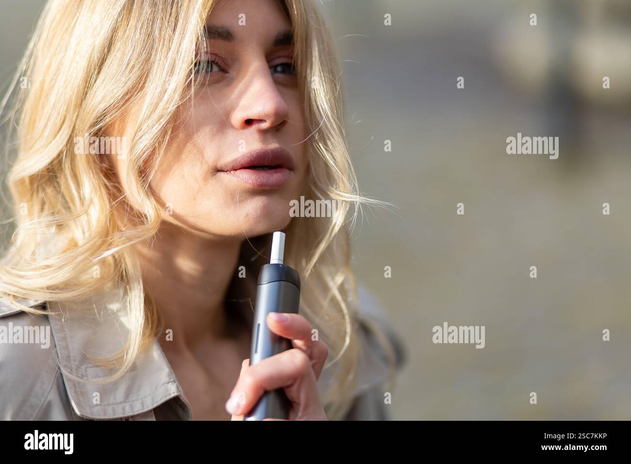 A woman is standing outside, holding a personal grooming device near ...