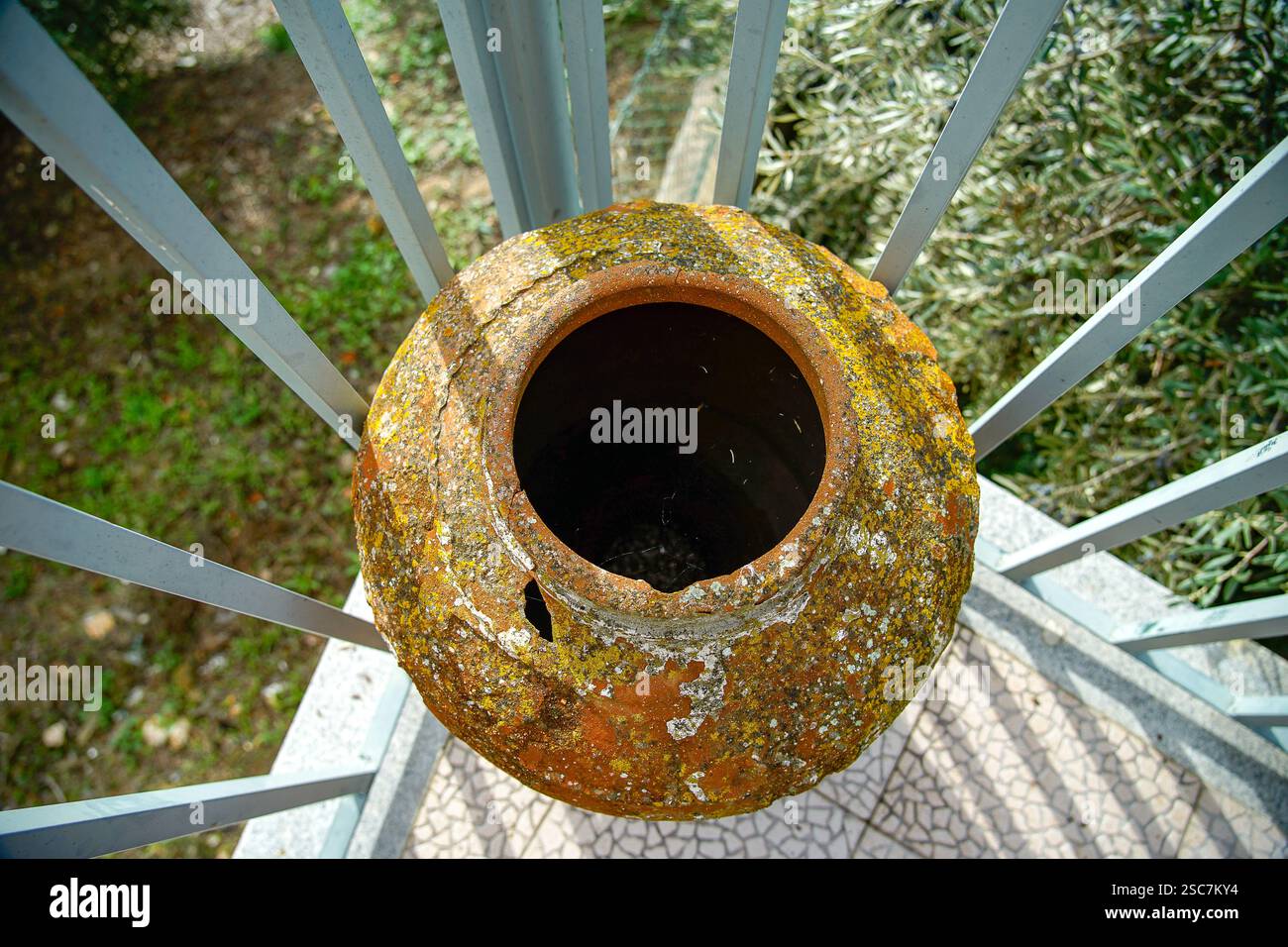 Old clay pot seen from above against the veranda with vertical metal ...