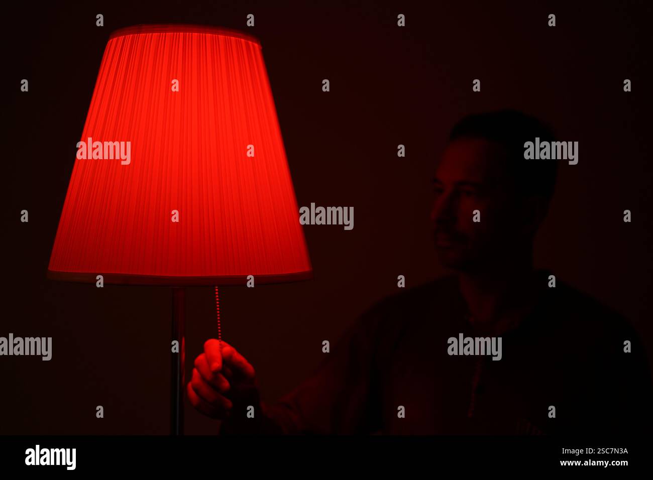 Lamp with strong red light on the left side under black background ...