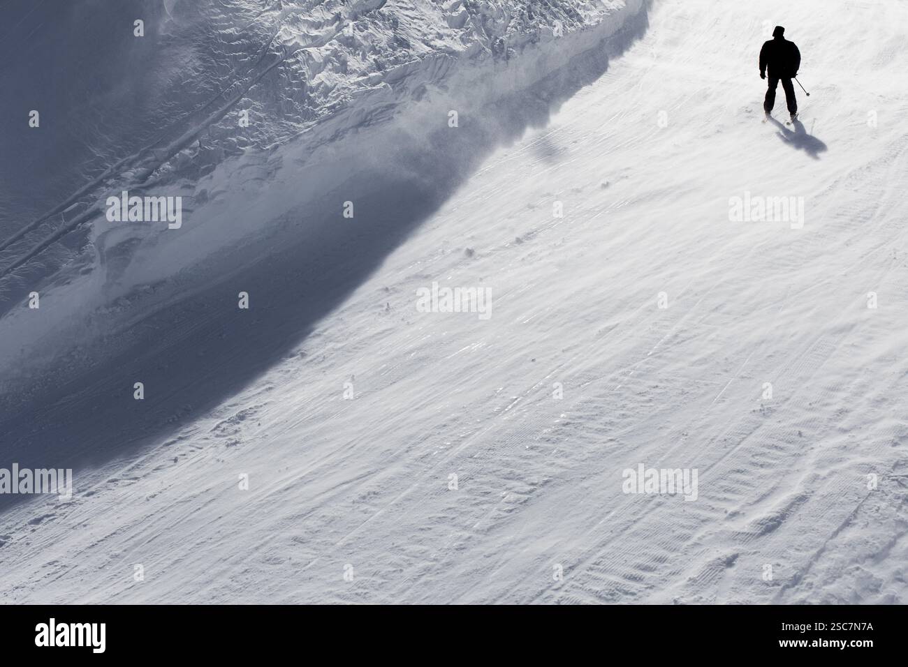 A striking scene featuring a lone skier navigating a snowy mountainside ...