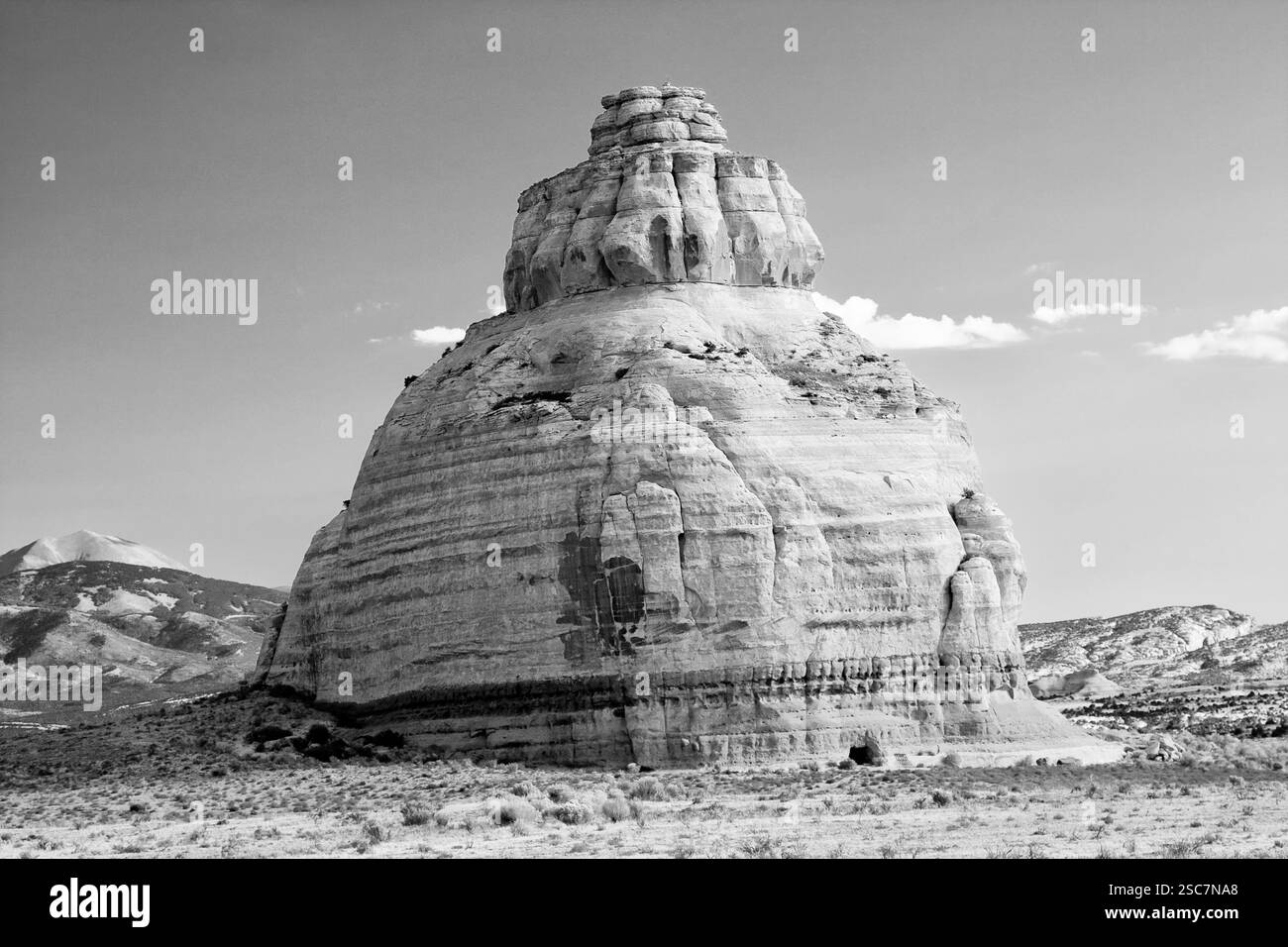 A large rock formation in the desert. The rock is very tall and has a ...