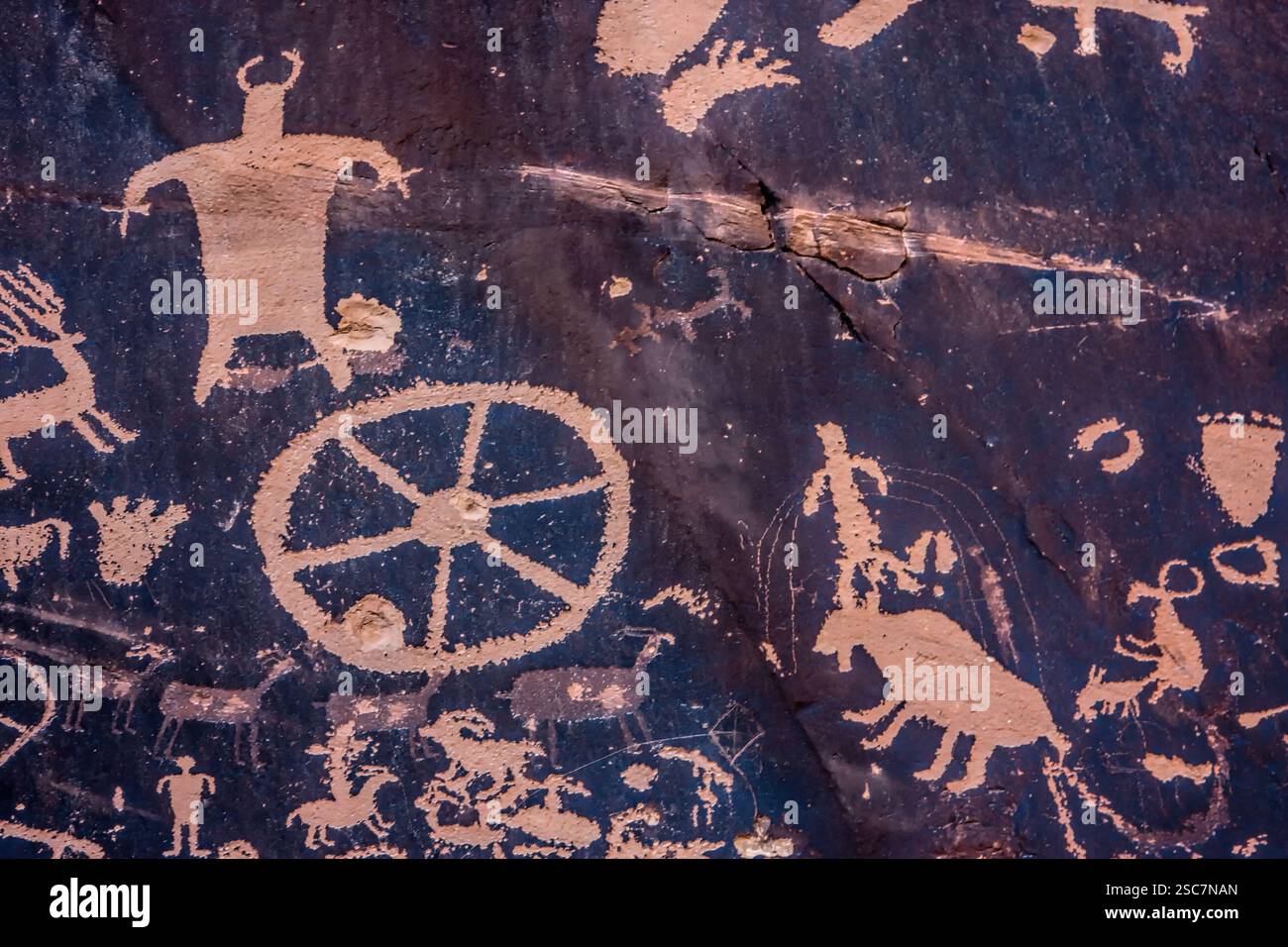 The rock is covered in drawings of various animals and a wheel. The ...