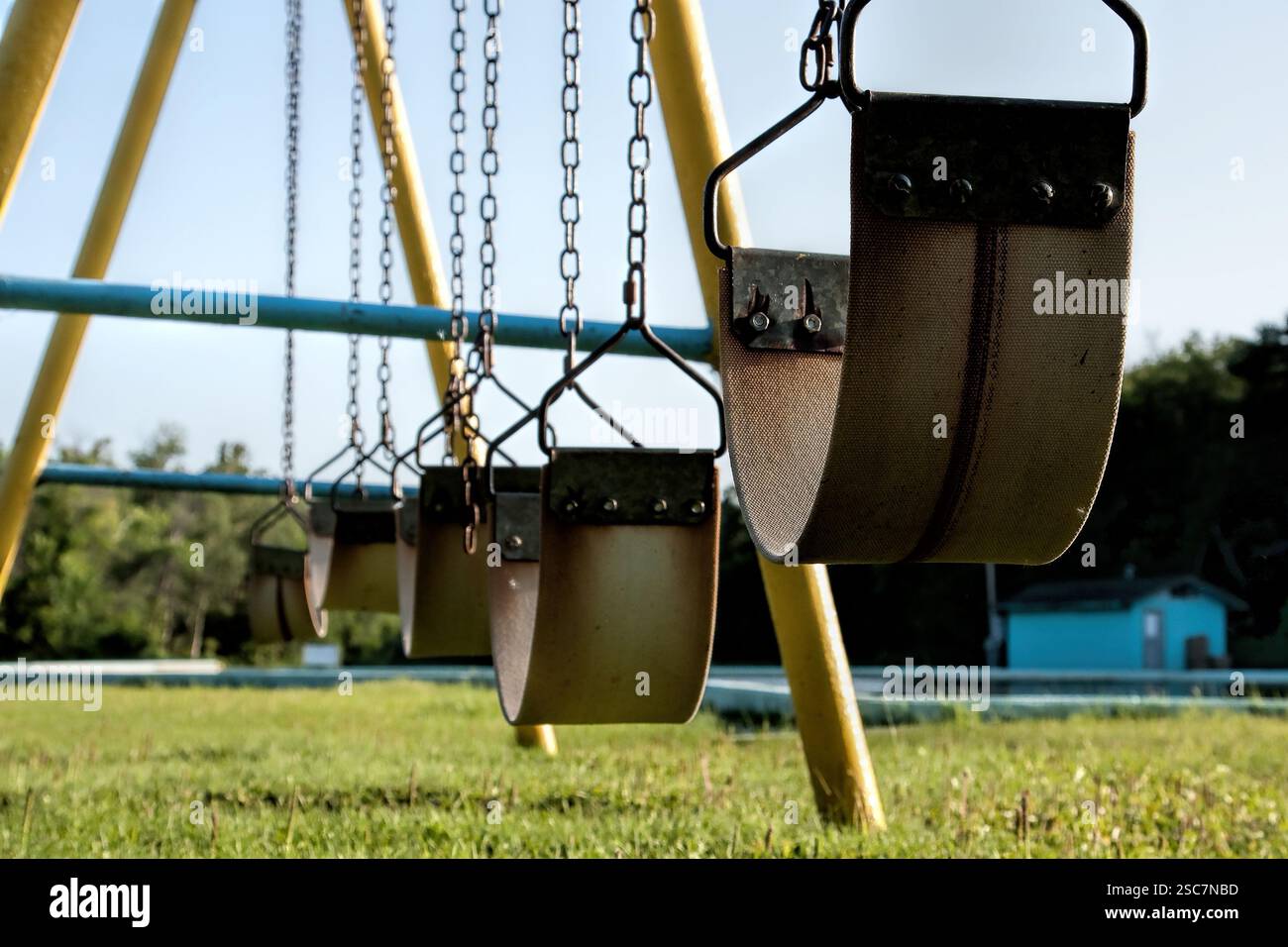 A swing set with four swings and a yellow metal frame. The swings are ...