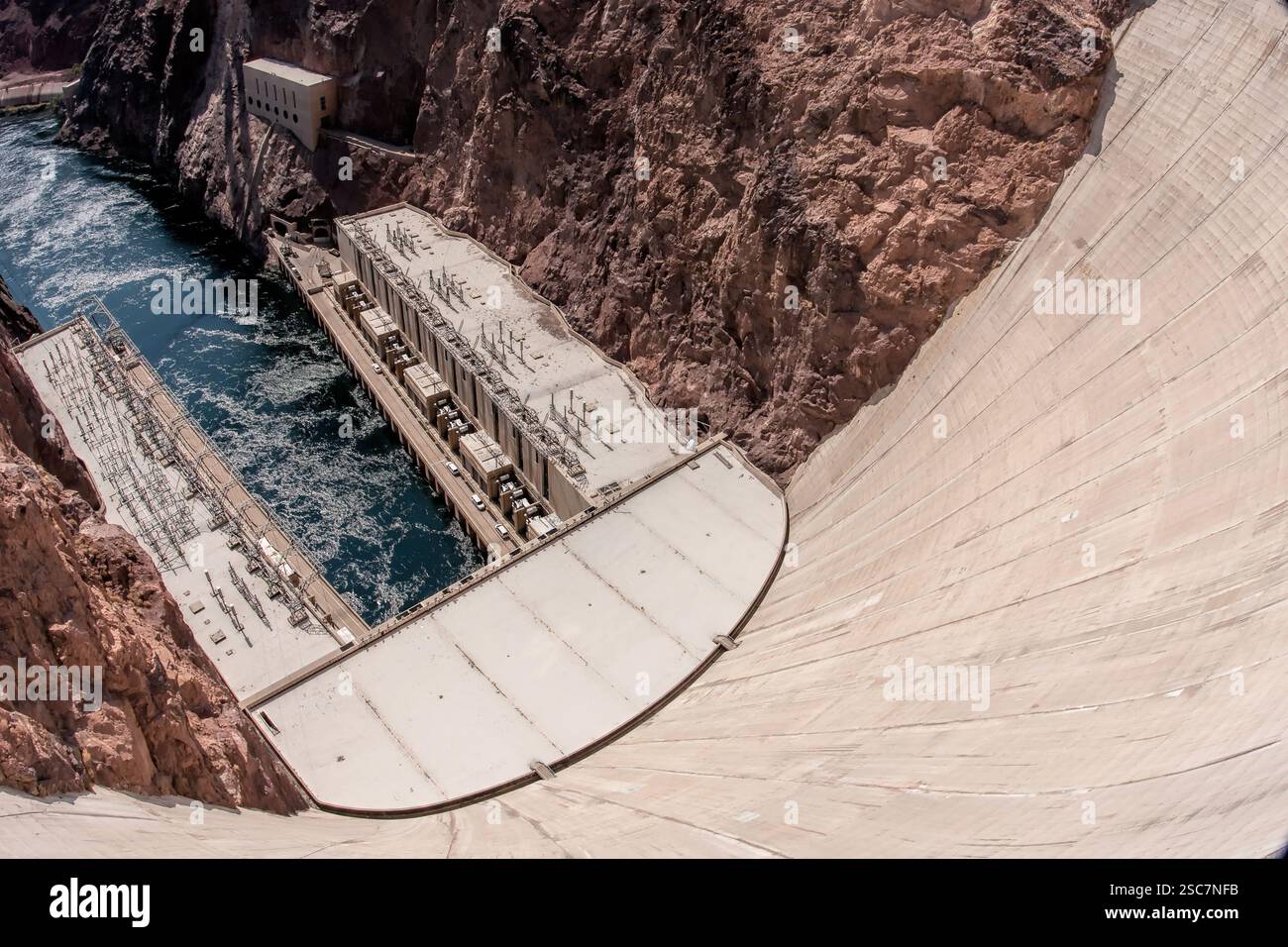 A large dam is built on a river. The dam is white and is surrounded by ...