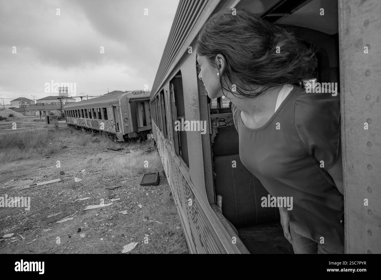 female passenger with windblown hair at the window of a run-down train ...