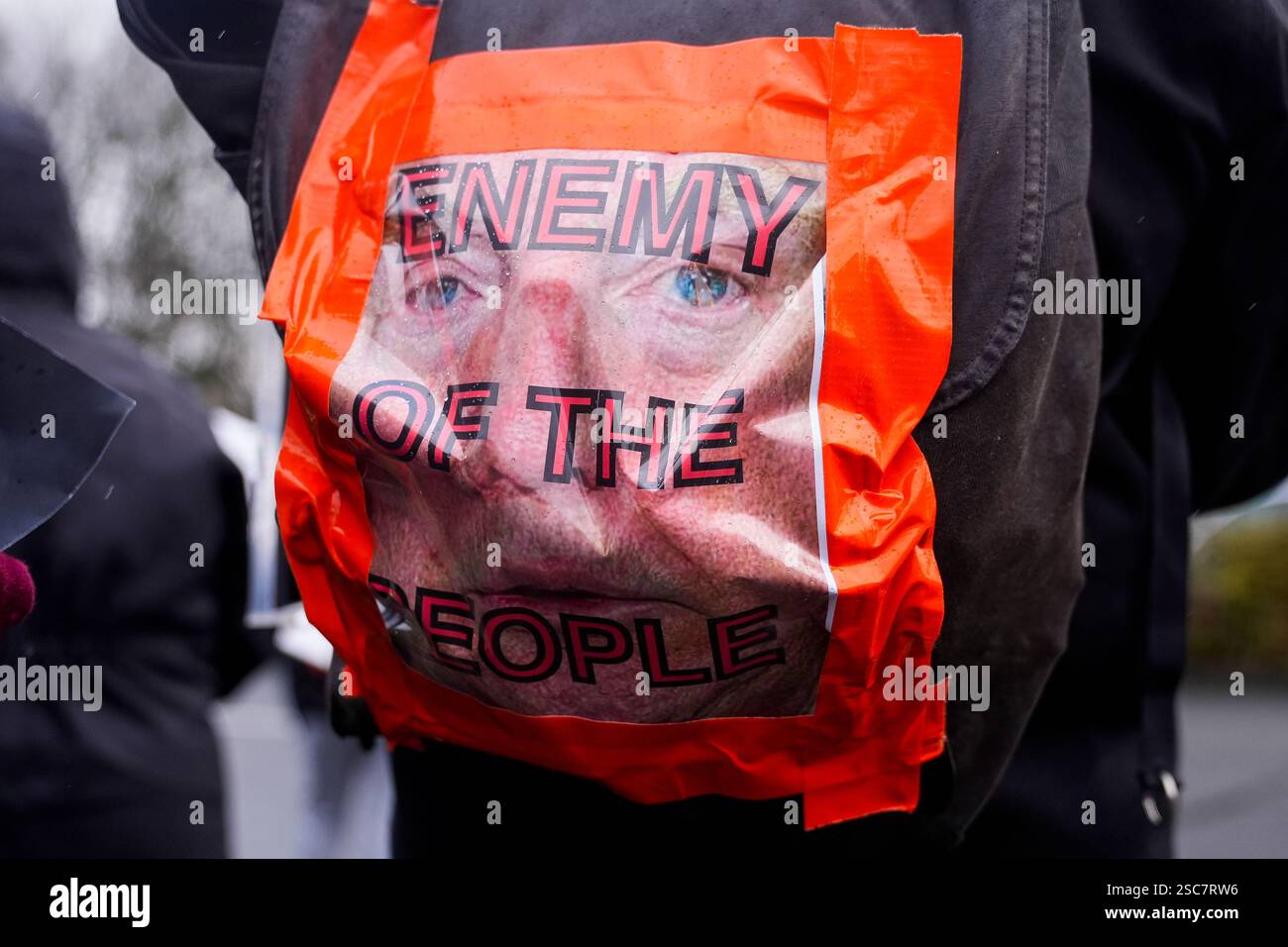 An image of President Donald Trump is taped to a protester's backpack ...