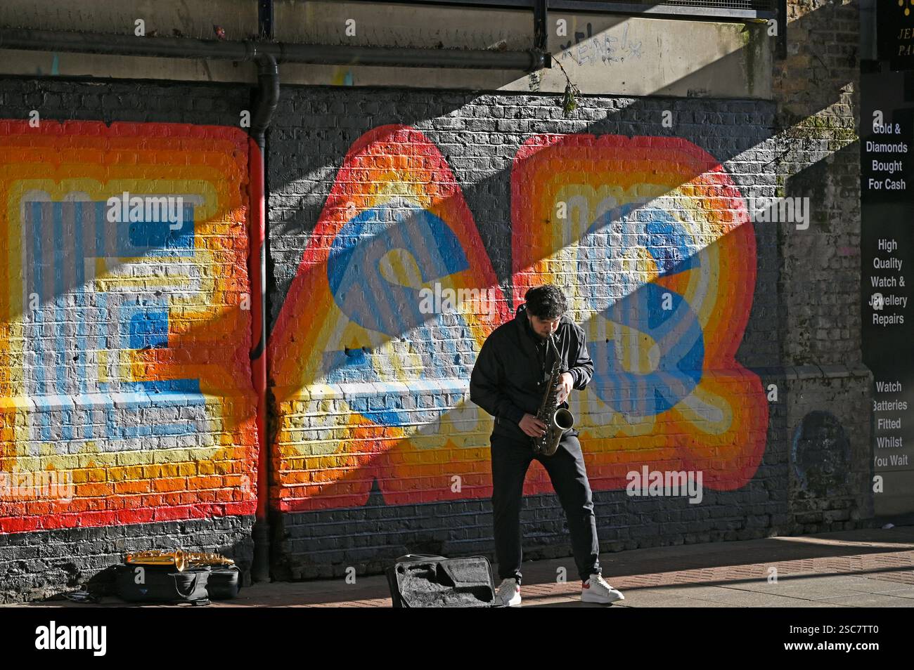 Busking in front of a mural under the railway bridge in the High Street ...