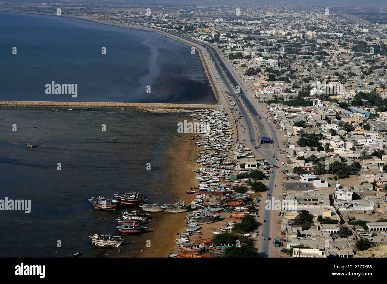 Fishers' boats are docked along the beach next to a new built highway ...
