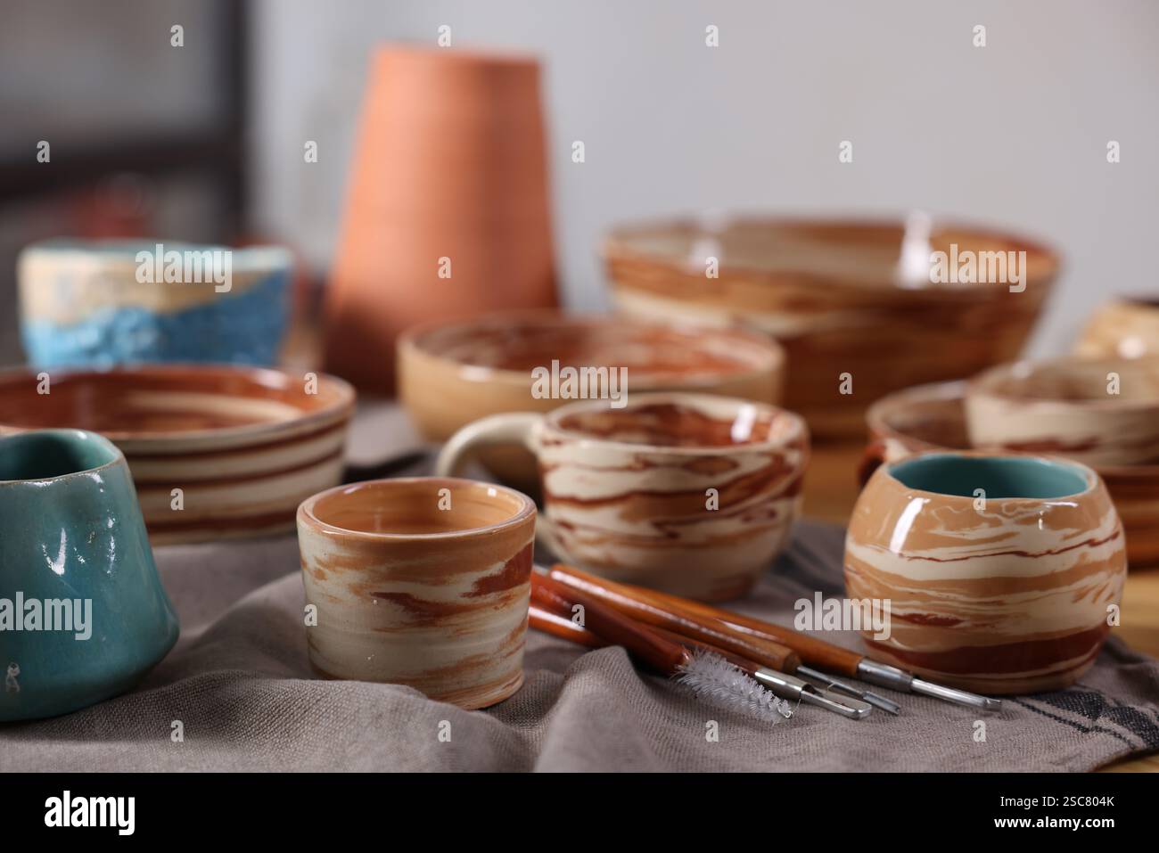 Different beautiful pottery and set of clay crafting tools on table ...