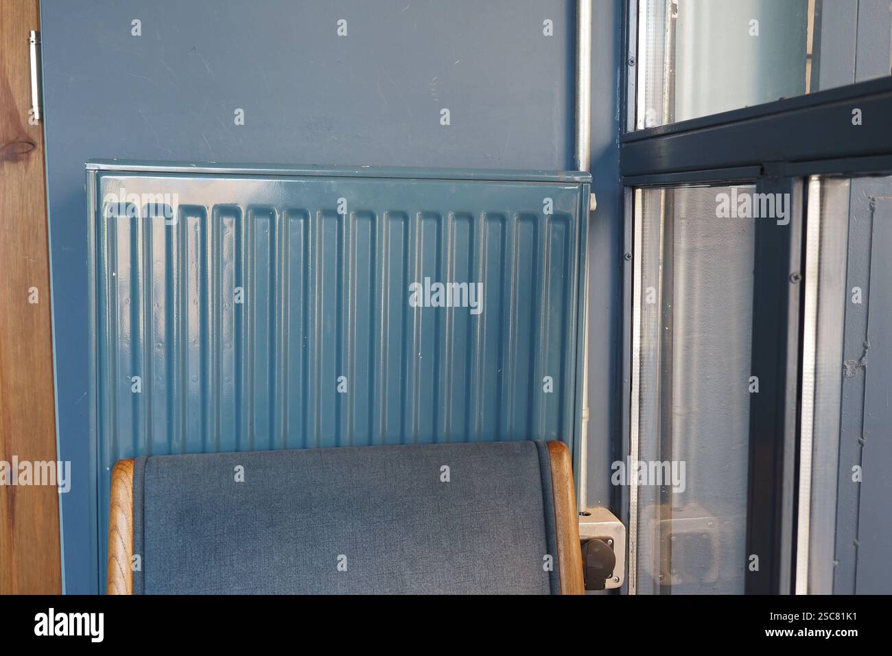 Cozy corner with a radiator and a blue chair in a room Stock Photo - Alamy