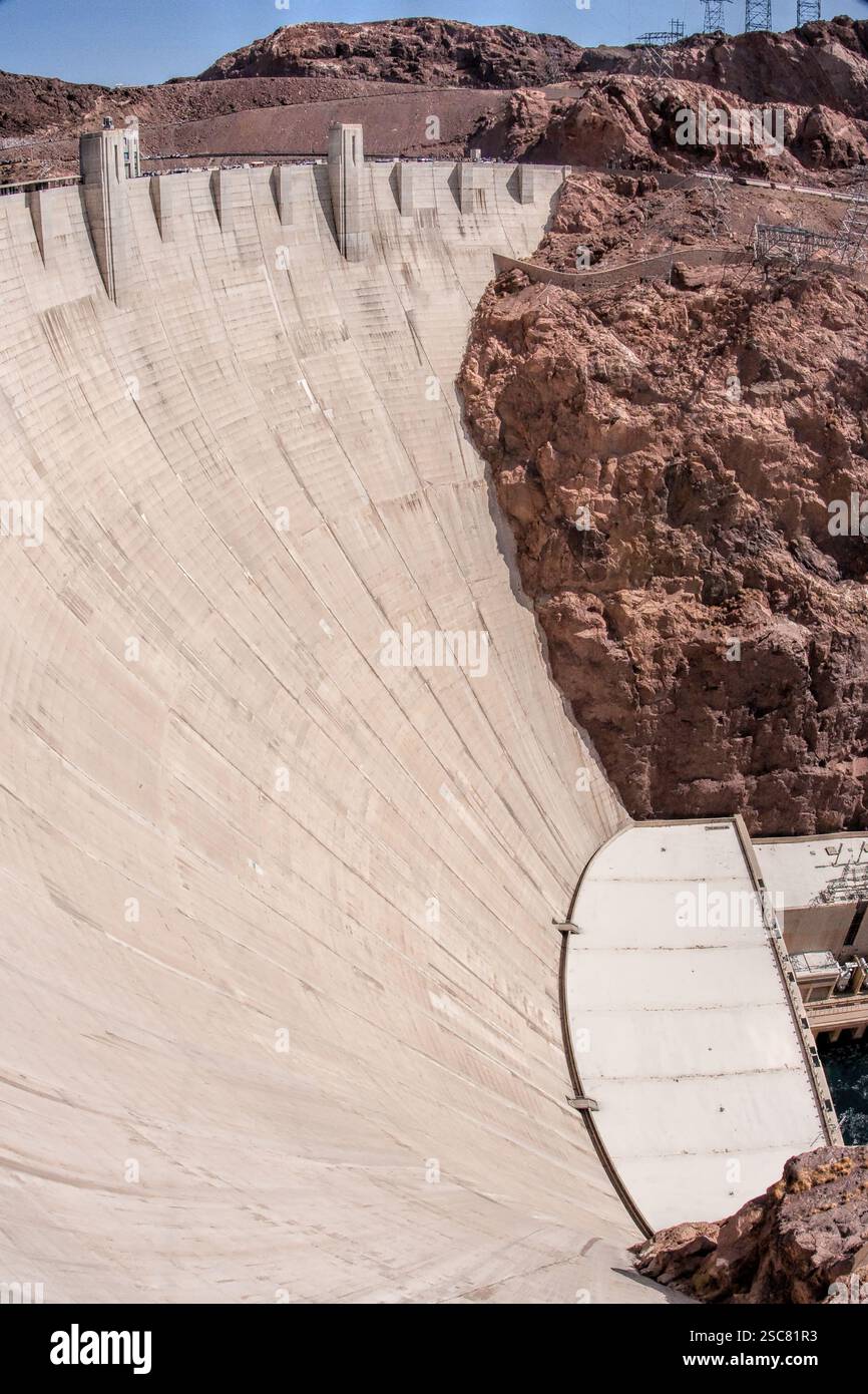 A large dam is built on a rocky mountain. The dam is white and has a ...
