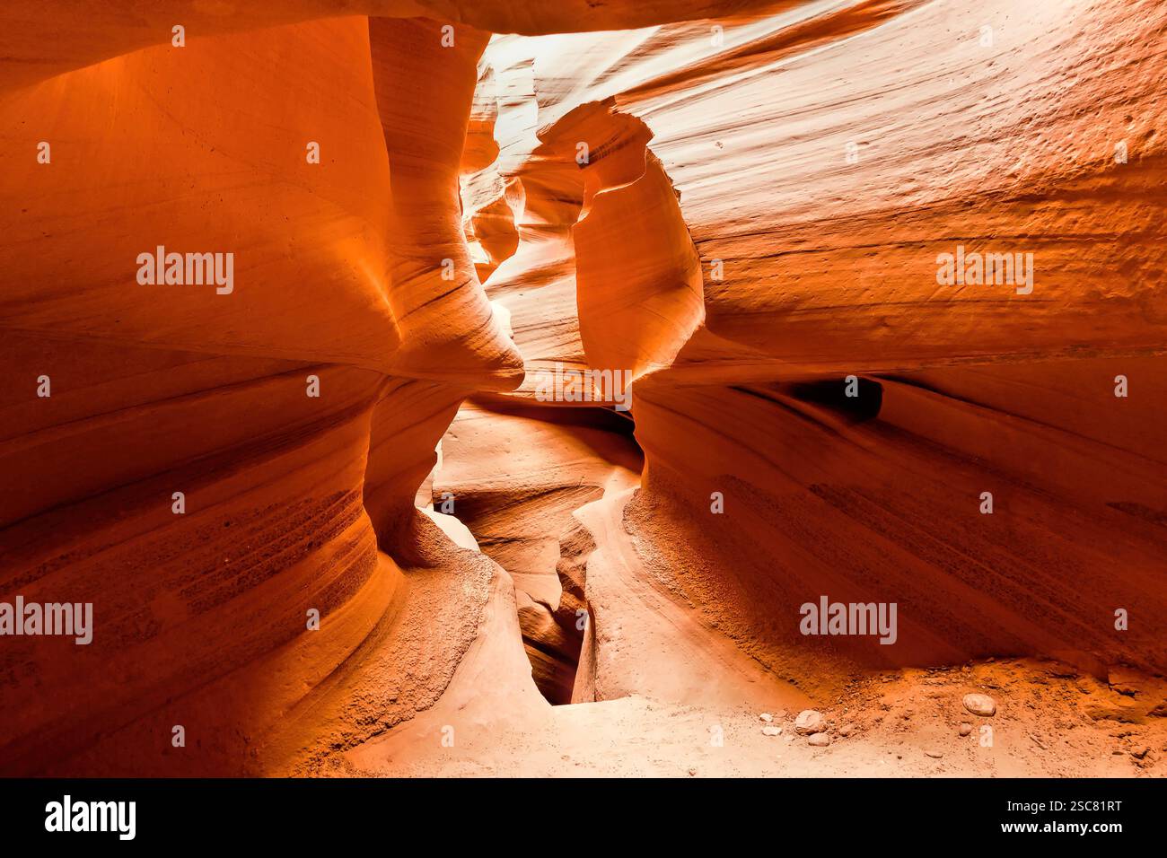 A narrow canyon with a hole in the middle. The walls are orange and the ...