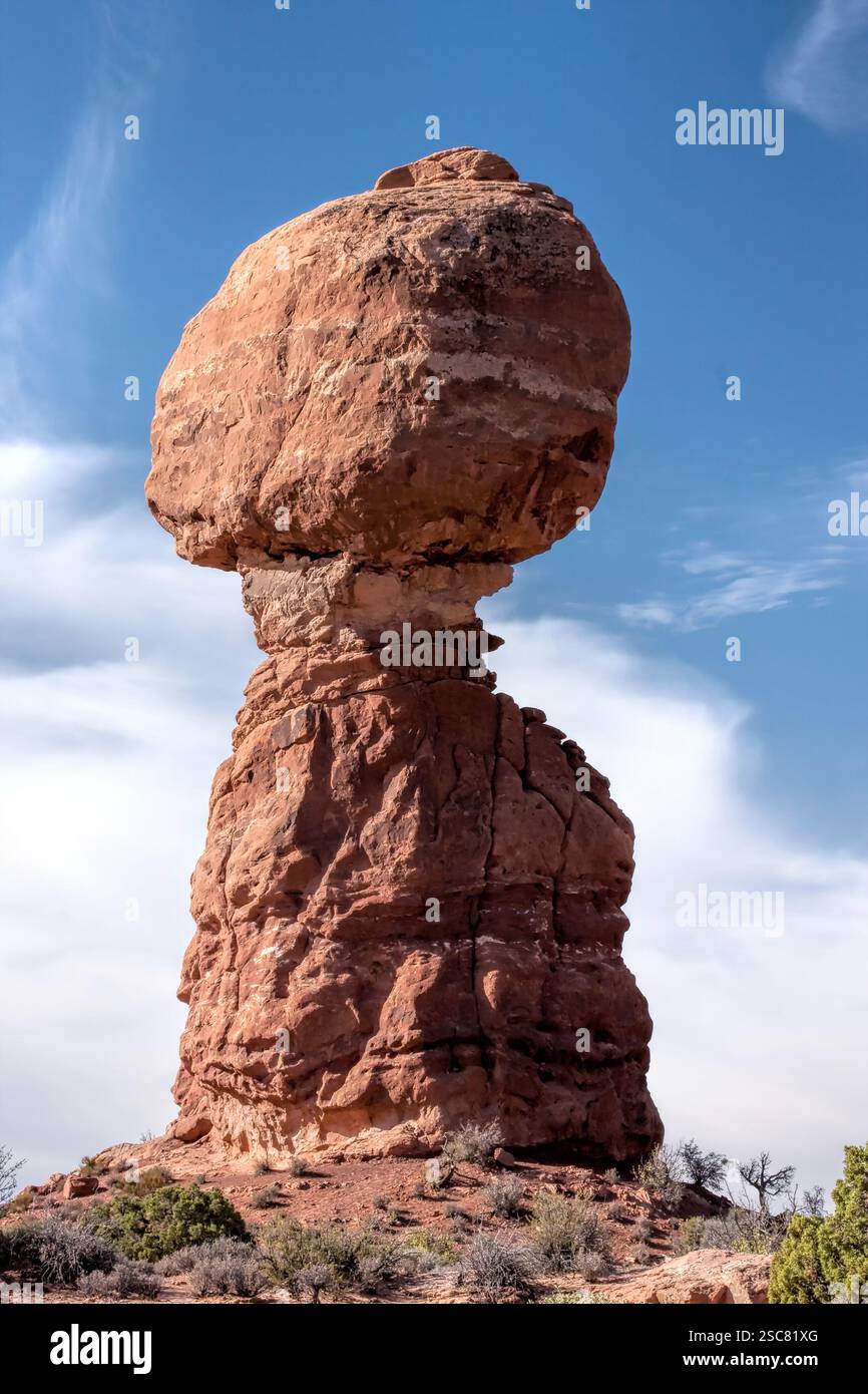 A large rock with a pointy top. The rock is brown and has a small hole ...