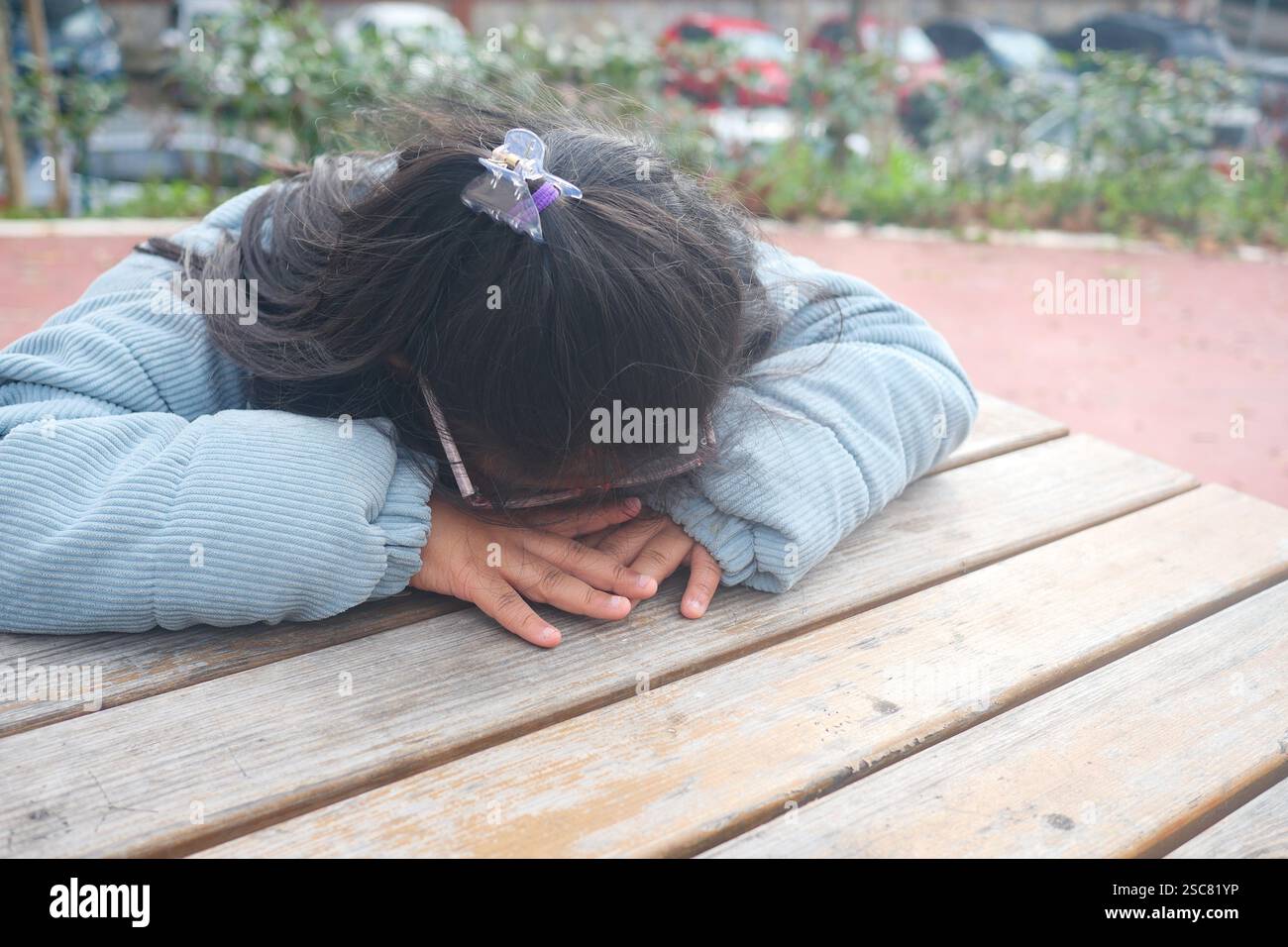 Child resting with head on table in a park during daytime Stock Photo ...
