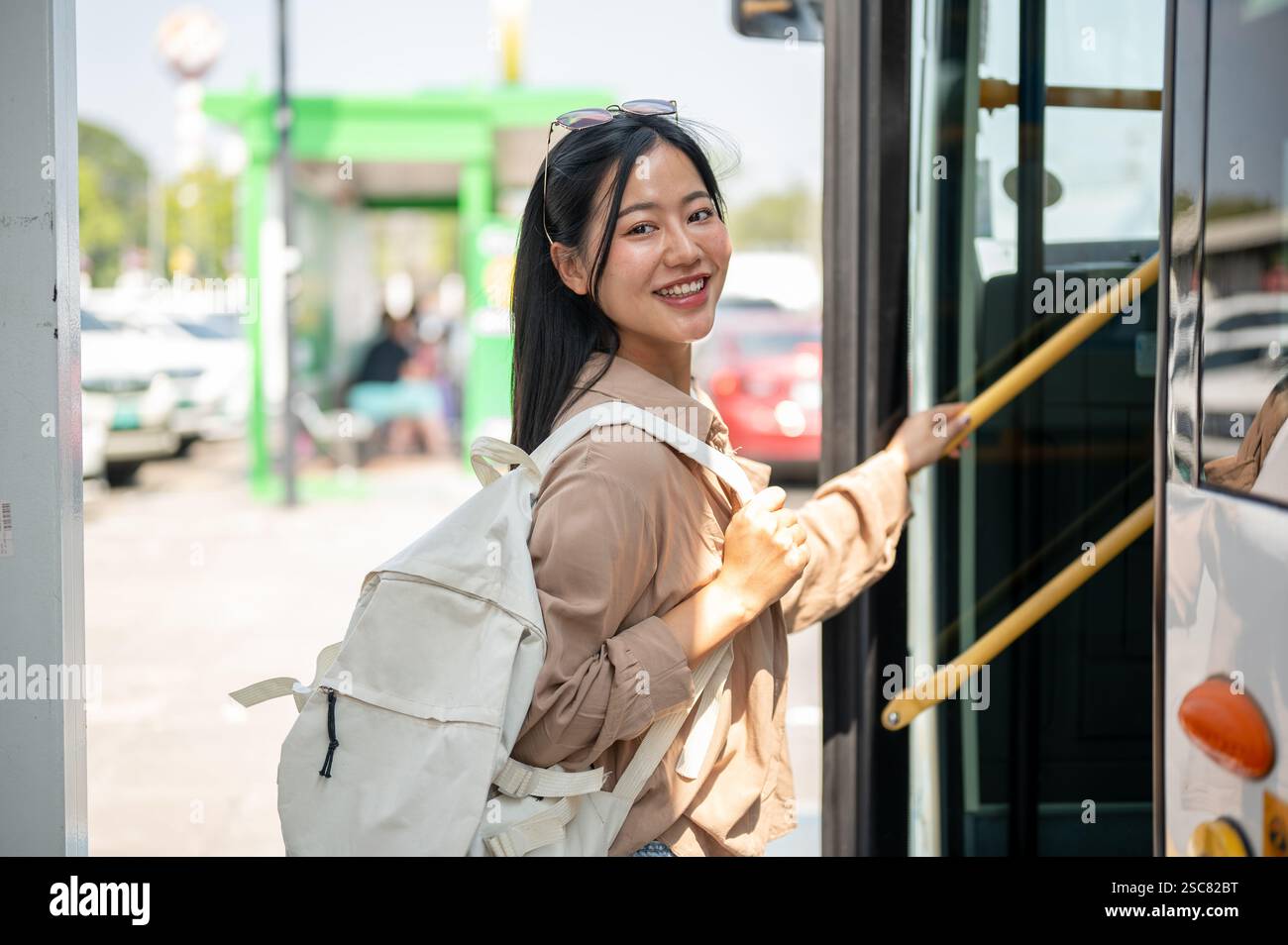 A beautiful, cheerful Asian woman in casual clothes with a backpack ...