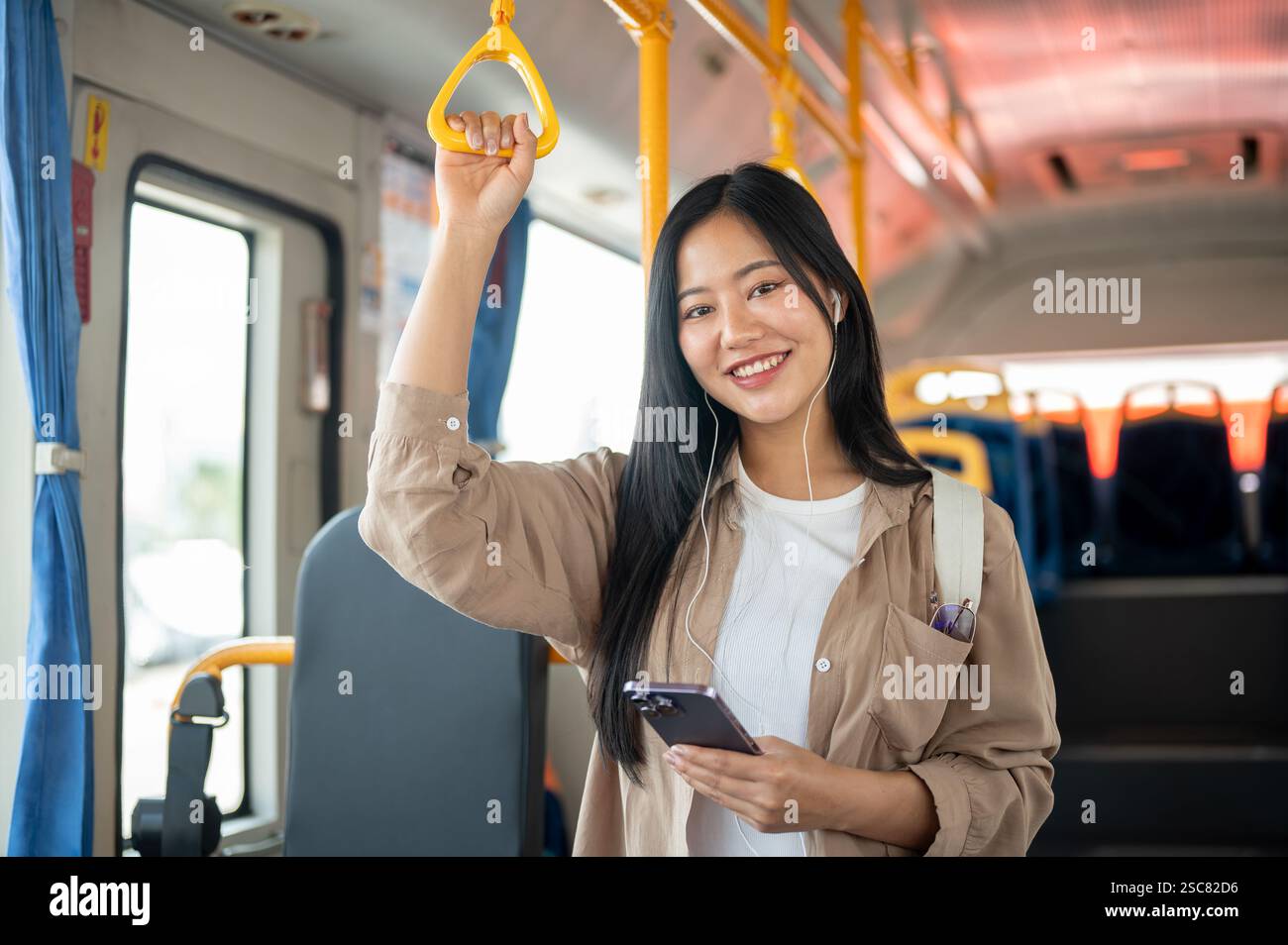 An attractive, beautiful Asian woman in casual clothes is on a bus ...