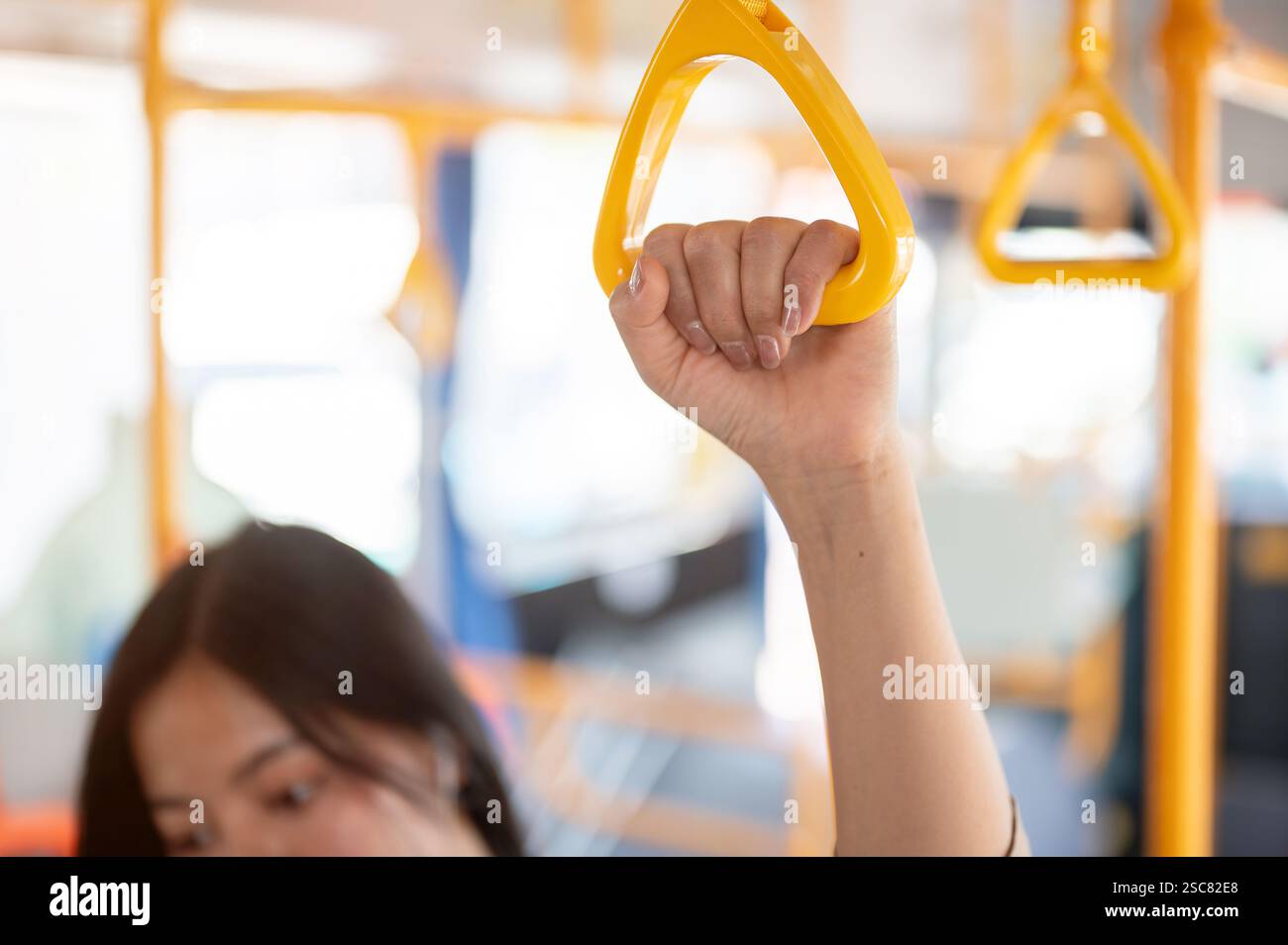 A close-up of a woman holding a handrail while commuting on a public ...