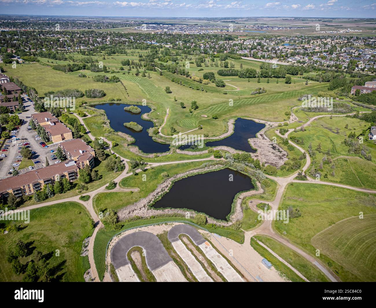 View of a golf course with a pond and a few houses in the background ...