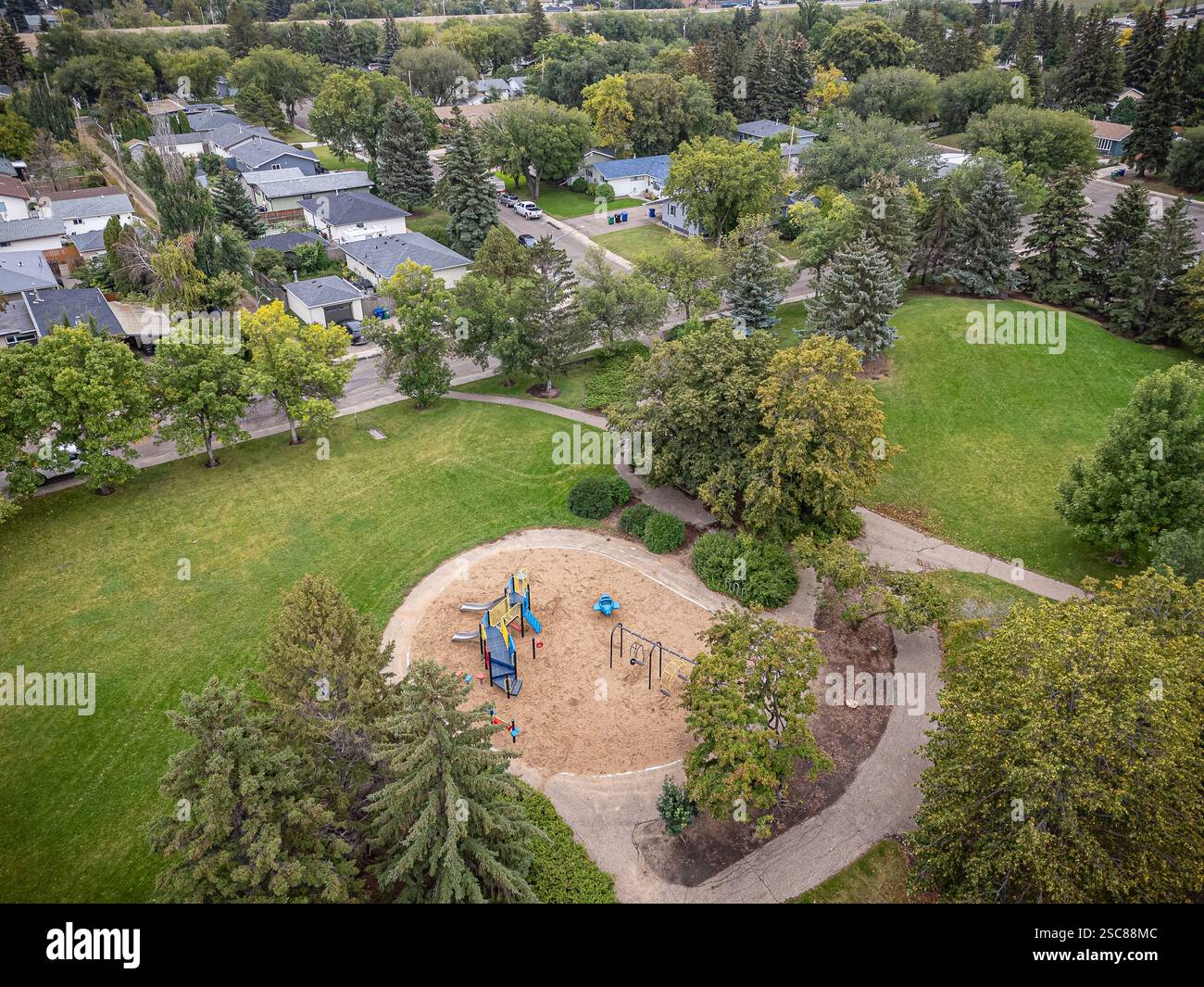Park with a playground and a path. The park is surrounded by houses ...