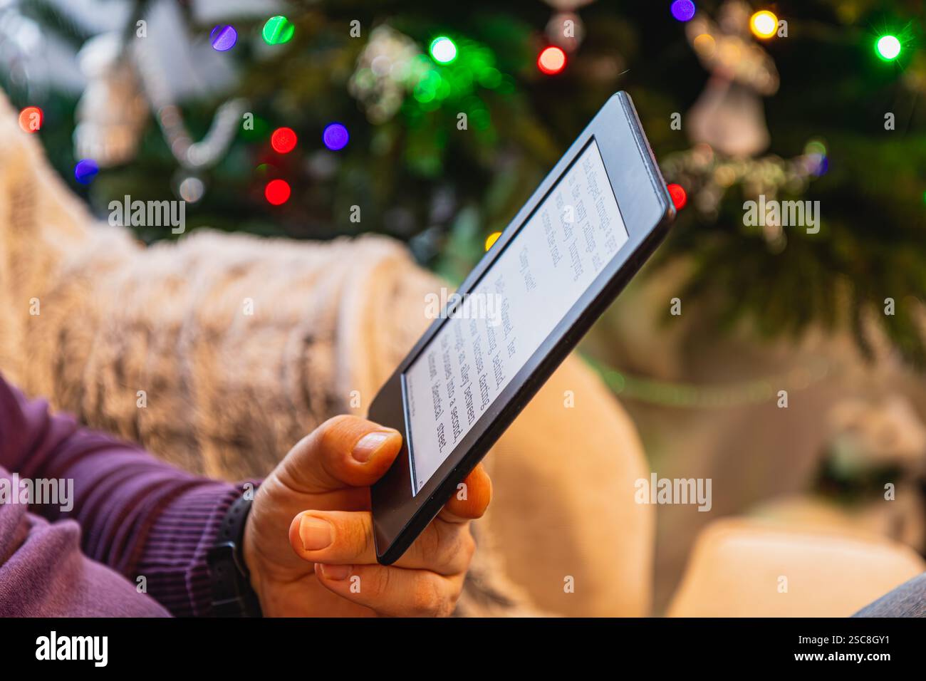 Engaging in e book reading, this cozy setting showcases a hand holding an e reader while ...