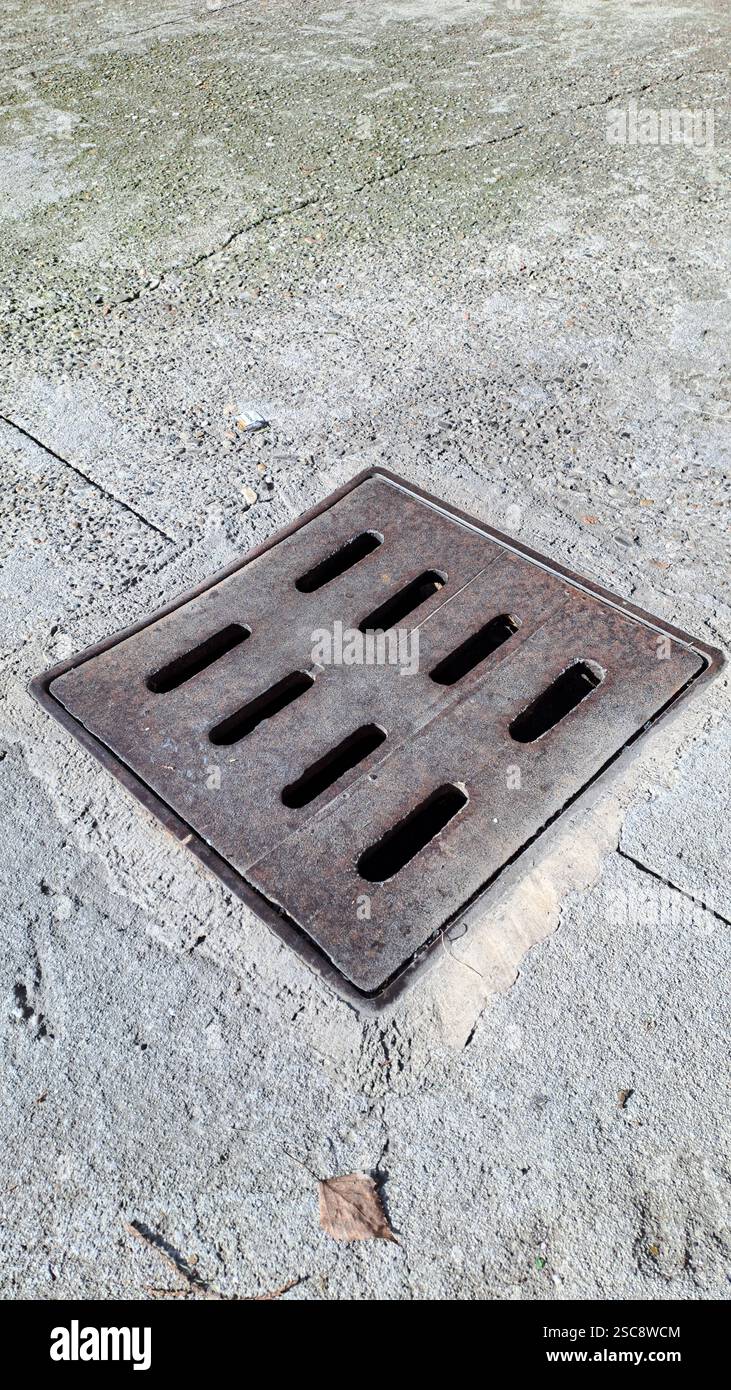 Metal manhole with oval slots on gray concrete, side view Stock Photo ...