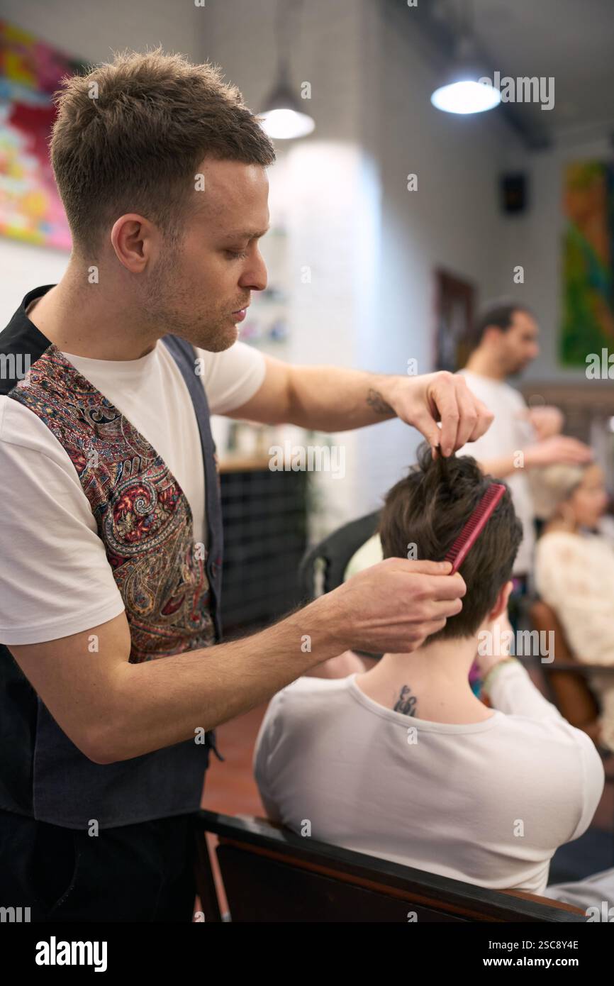 Hairdresser combing short hair of young female model in salon Stock ...