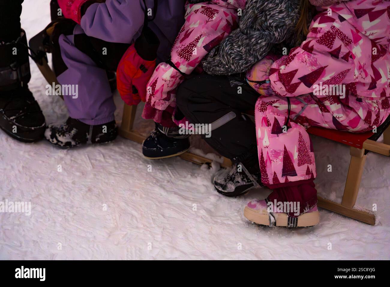 Children sitting on sleds in colorful winter outfits in the snow Stock ...