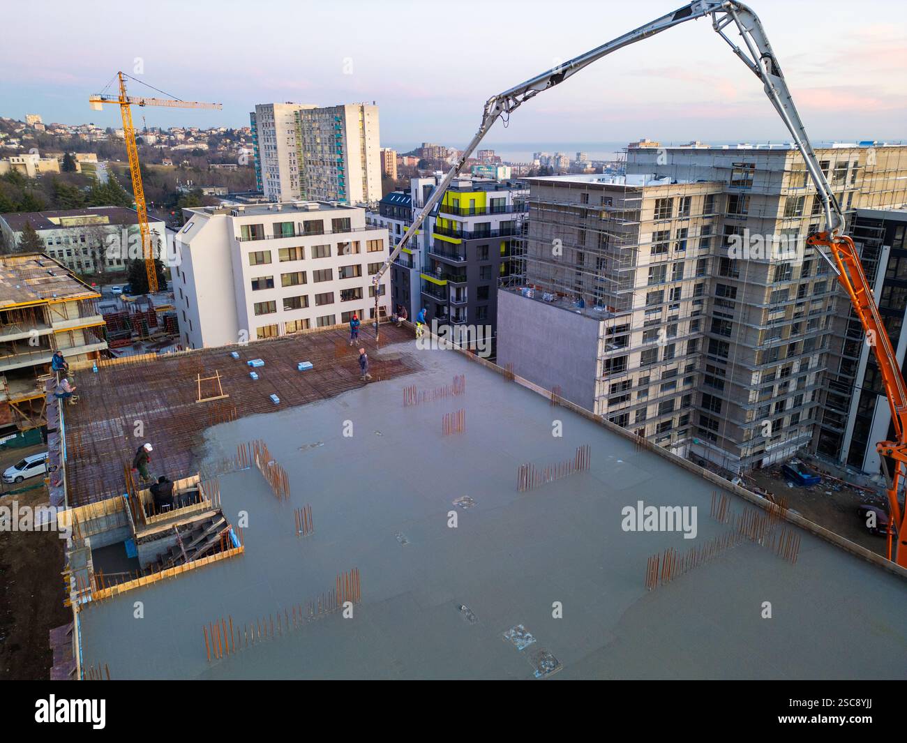 Aerial view of a construction site with a high-rise building under development. A concrete pump ...