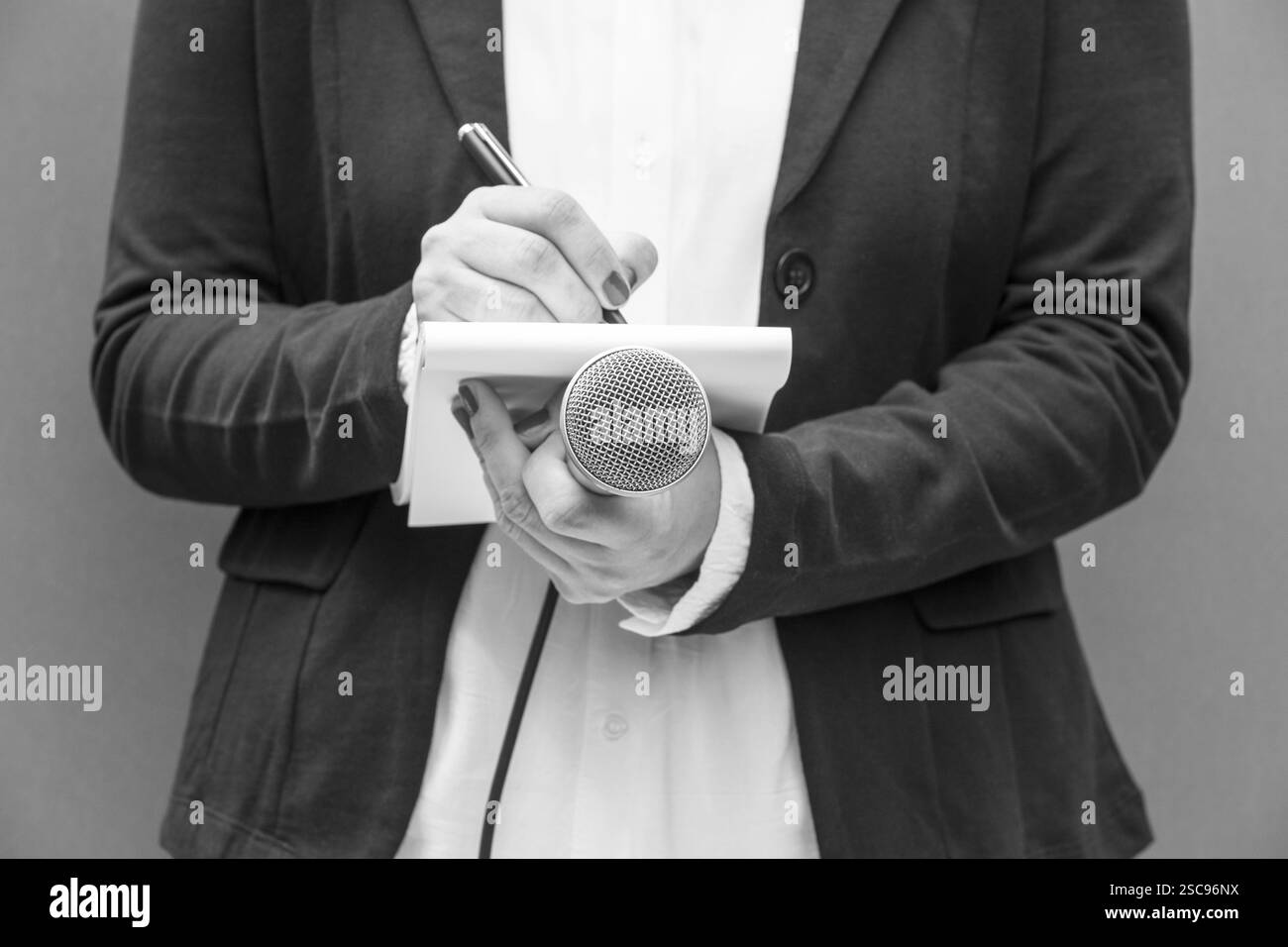 Female reporter at press conference or media event, writing notes ...