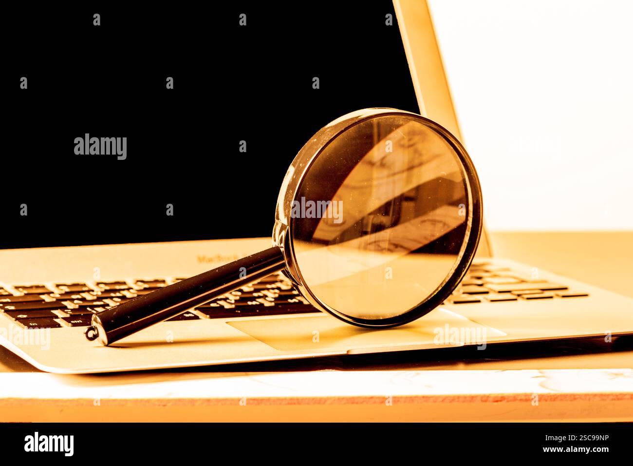 Closeup images of magnifying glass on laptop keyboard Stock Photo - Alamy