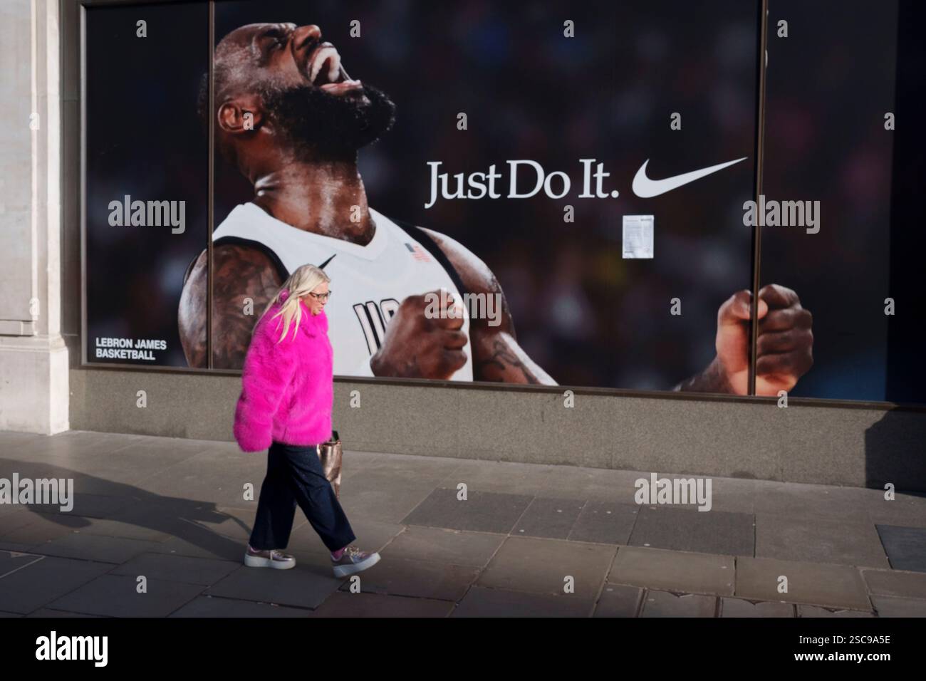 A shopper walks past a 'Just Do It' ad slogan that features NBA Los ...