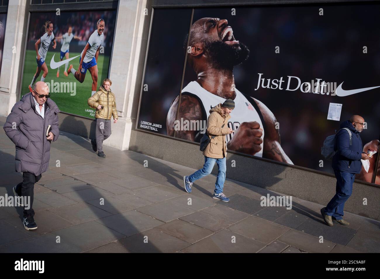 Shoppers walk past a 'Just Do It' ad slogan that features NBA Los ...