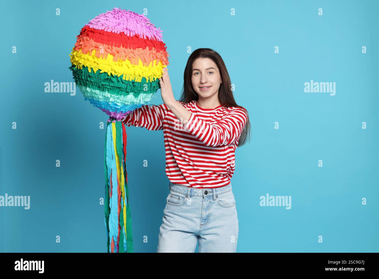 Happy woman with pinata on light blue background Stock Photo - Alamy