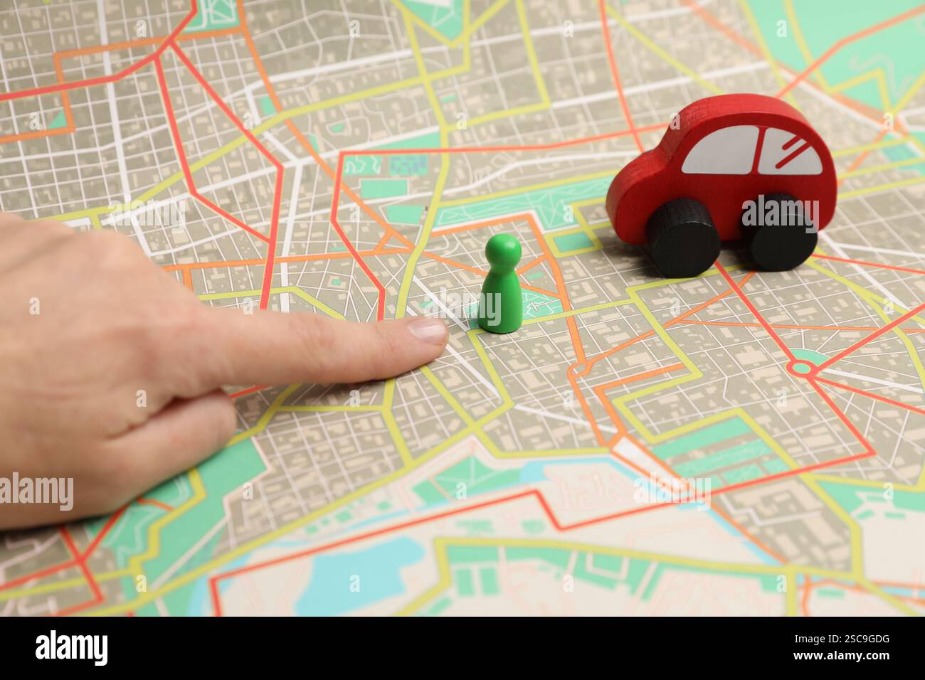 Woman pointing at city map near human figure and toy car, closeup. Road ...