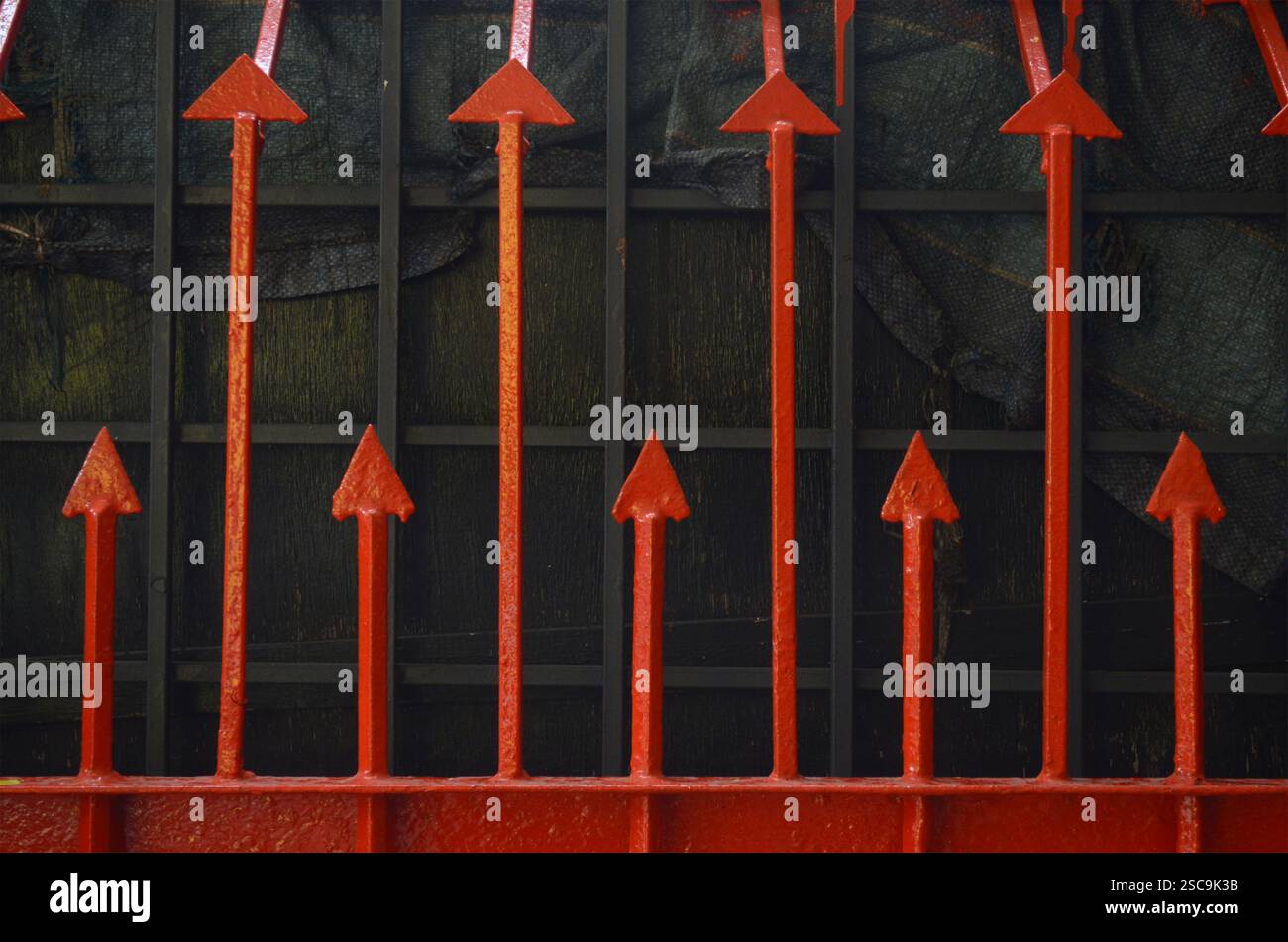 A close-up of a wrought iron fence with pointed red arrowhead finials ...