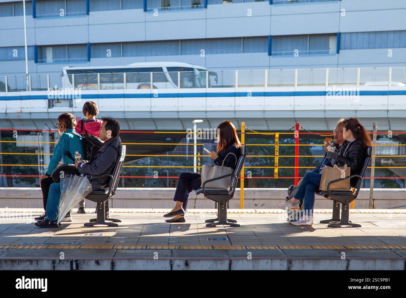 Kobe Station platform with passengers sitting on a bench on the station ...