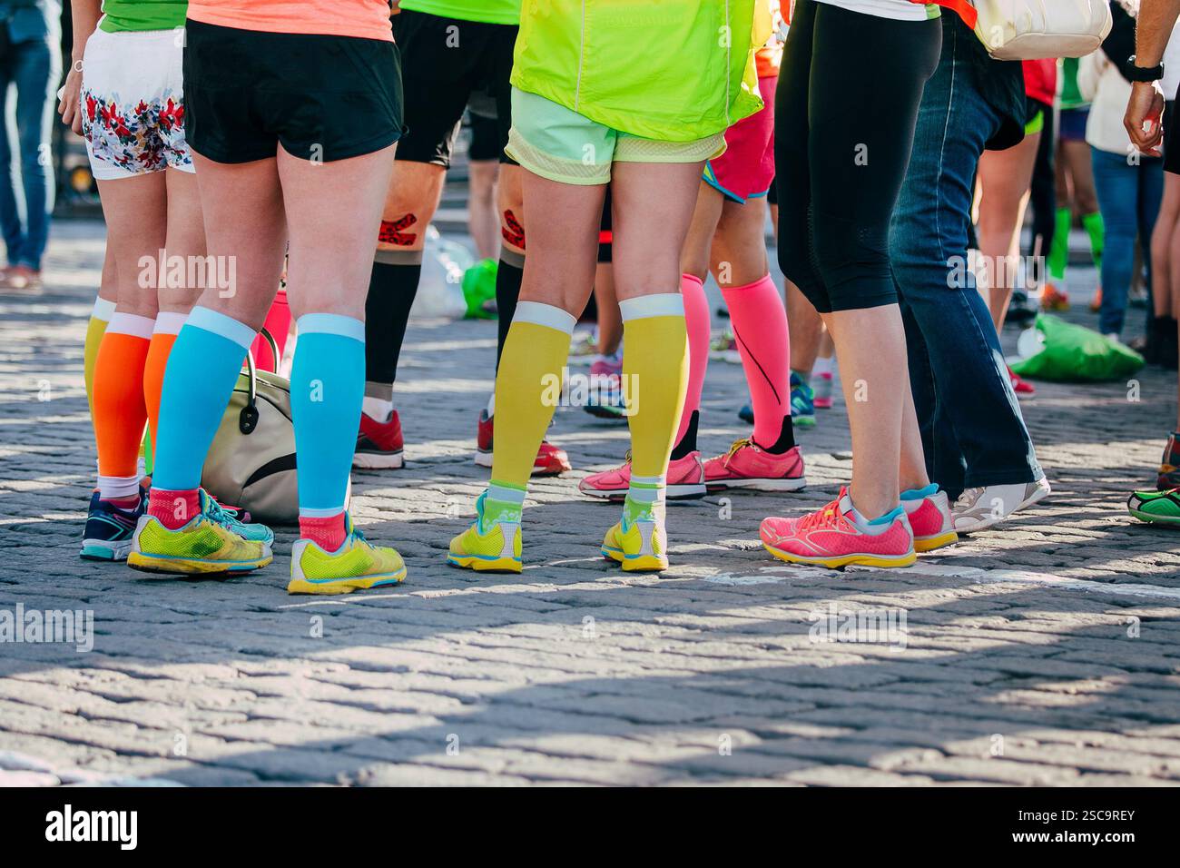 runners stand in lively area before marathon, showcasing vibrant socks ...