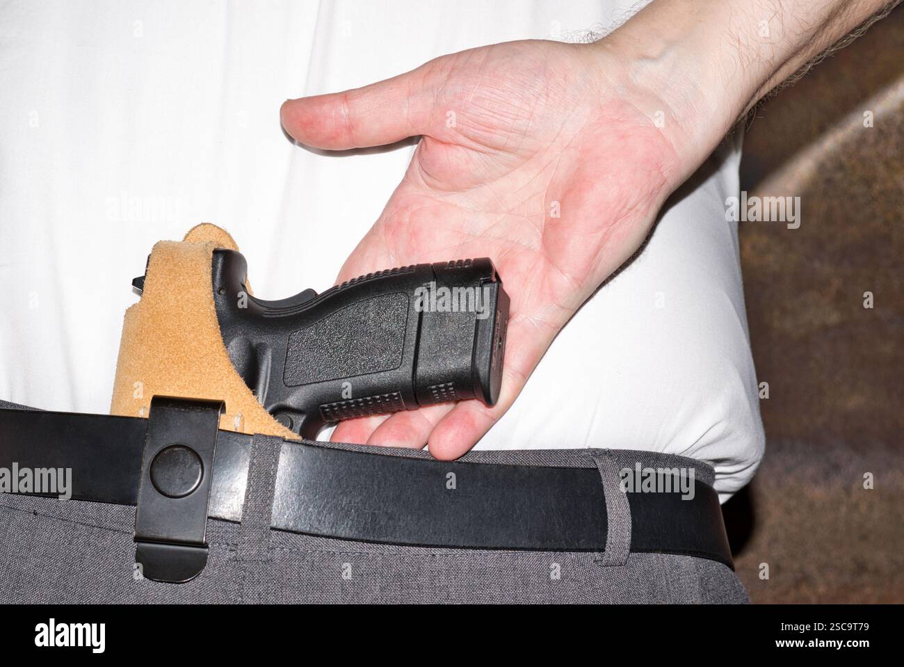 Hand reaching for gun behind the back holster draw concealed carry self ...