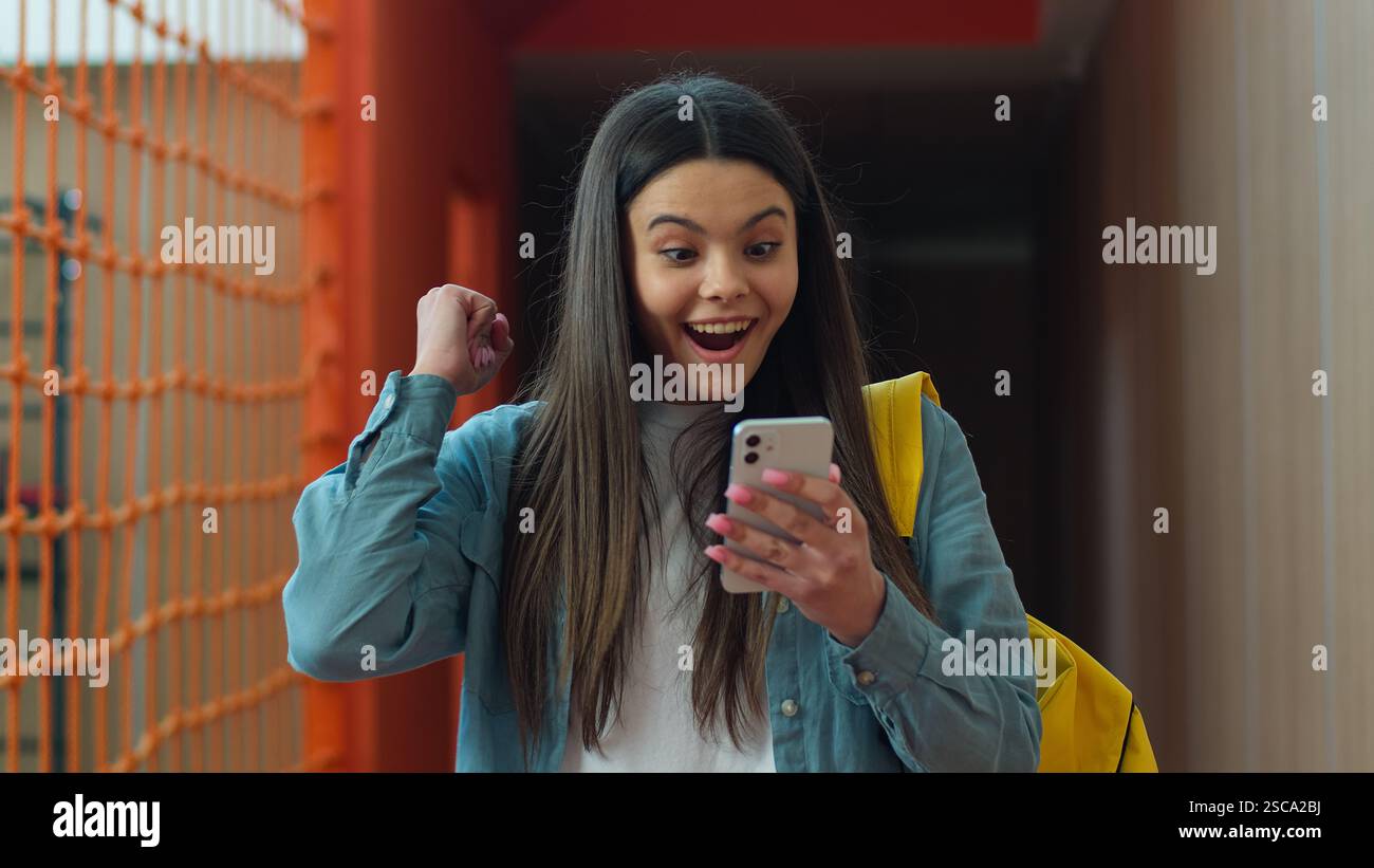 Happy smiling Caucasian student girl smile using mobile phone win ...