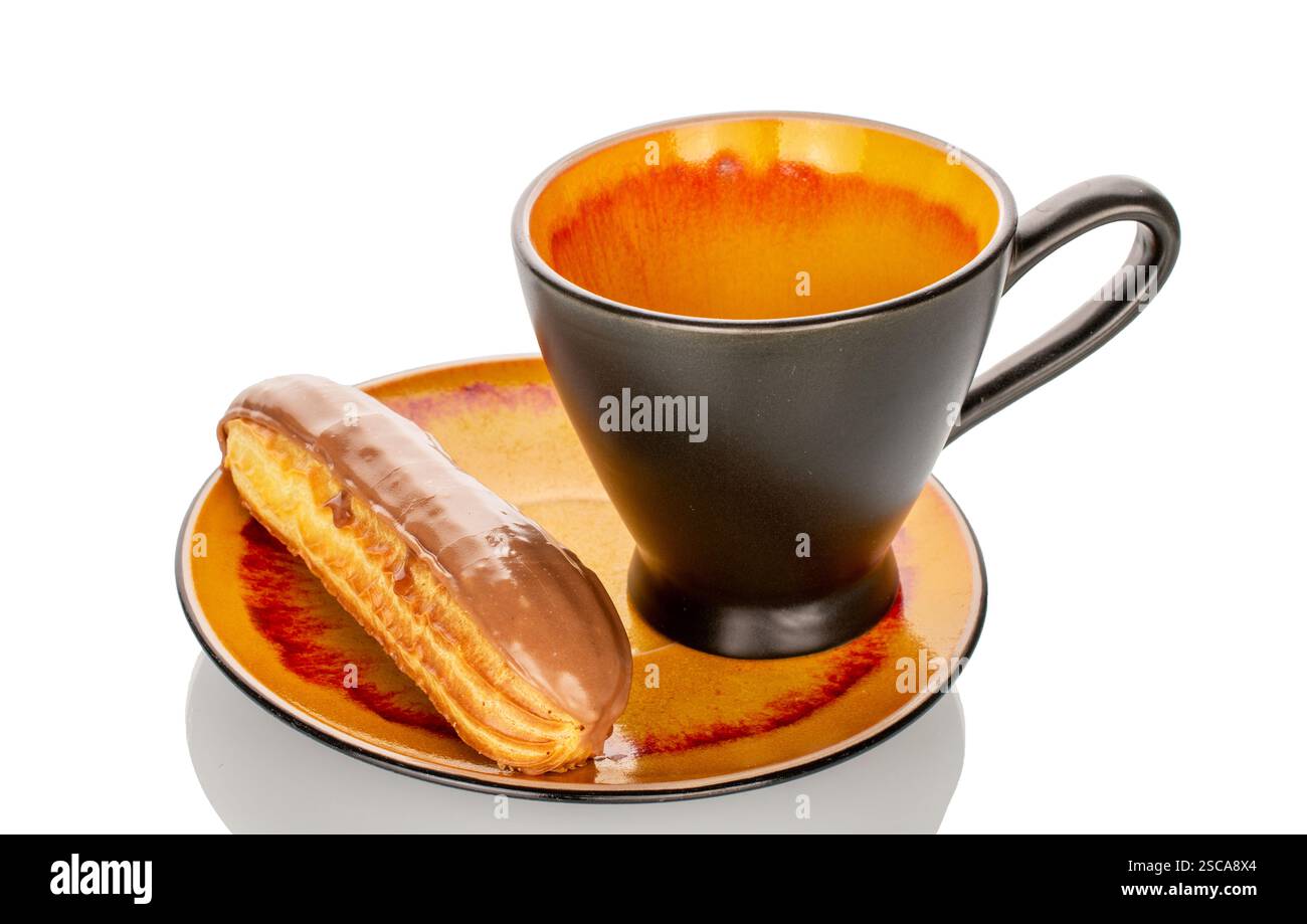One eclair with cream filling on a ceramic saucer with a cup, close-up ...
